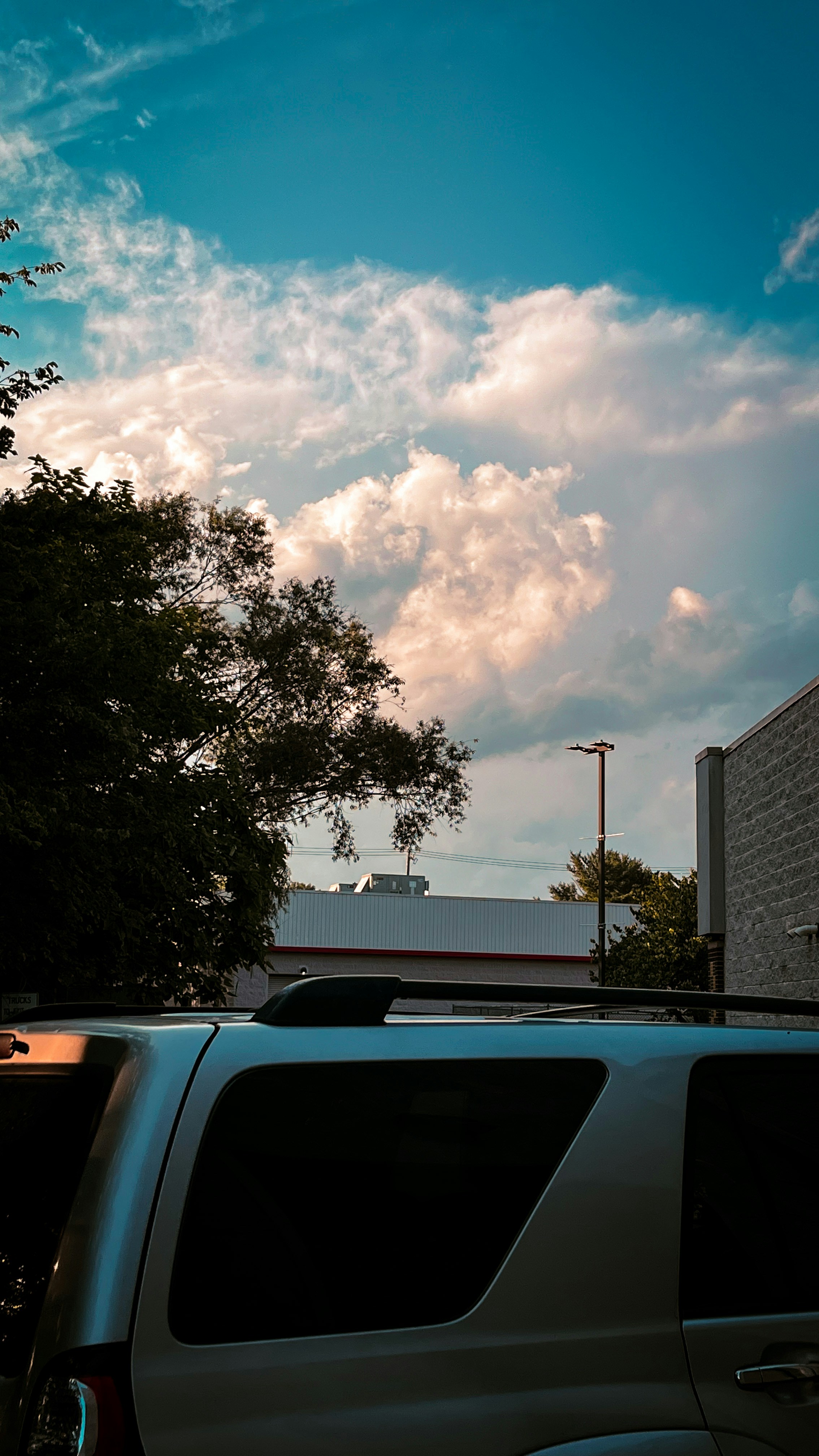 a car parked in front of a building under a cloudy sky