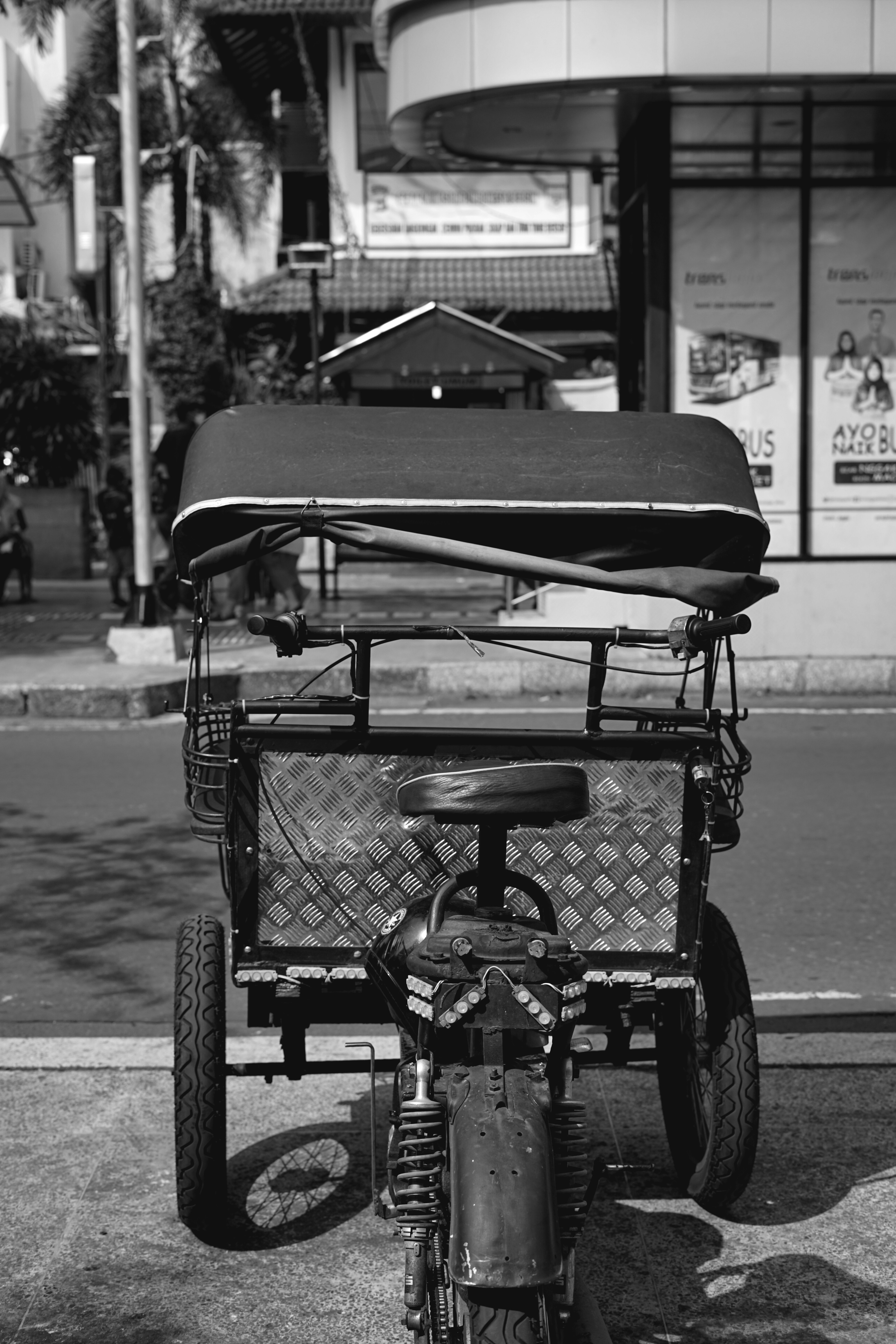 A three-wheeled vehicle parked on a city street, showcasing its unique design and urban setting.