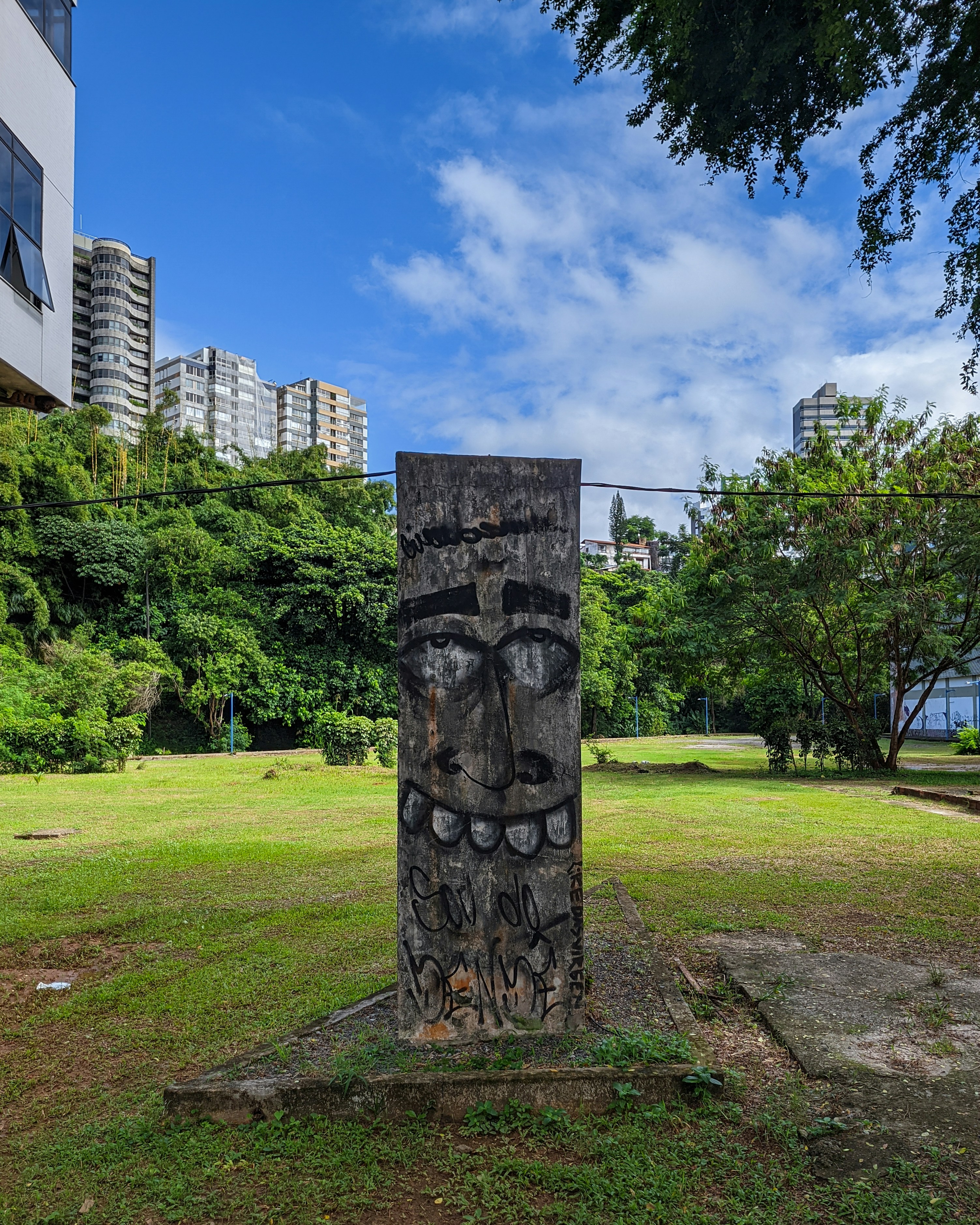 Graffitied Obelisk in a Green Urban Clearing Under a Bright Sky