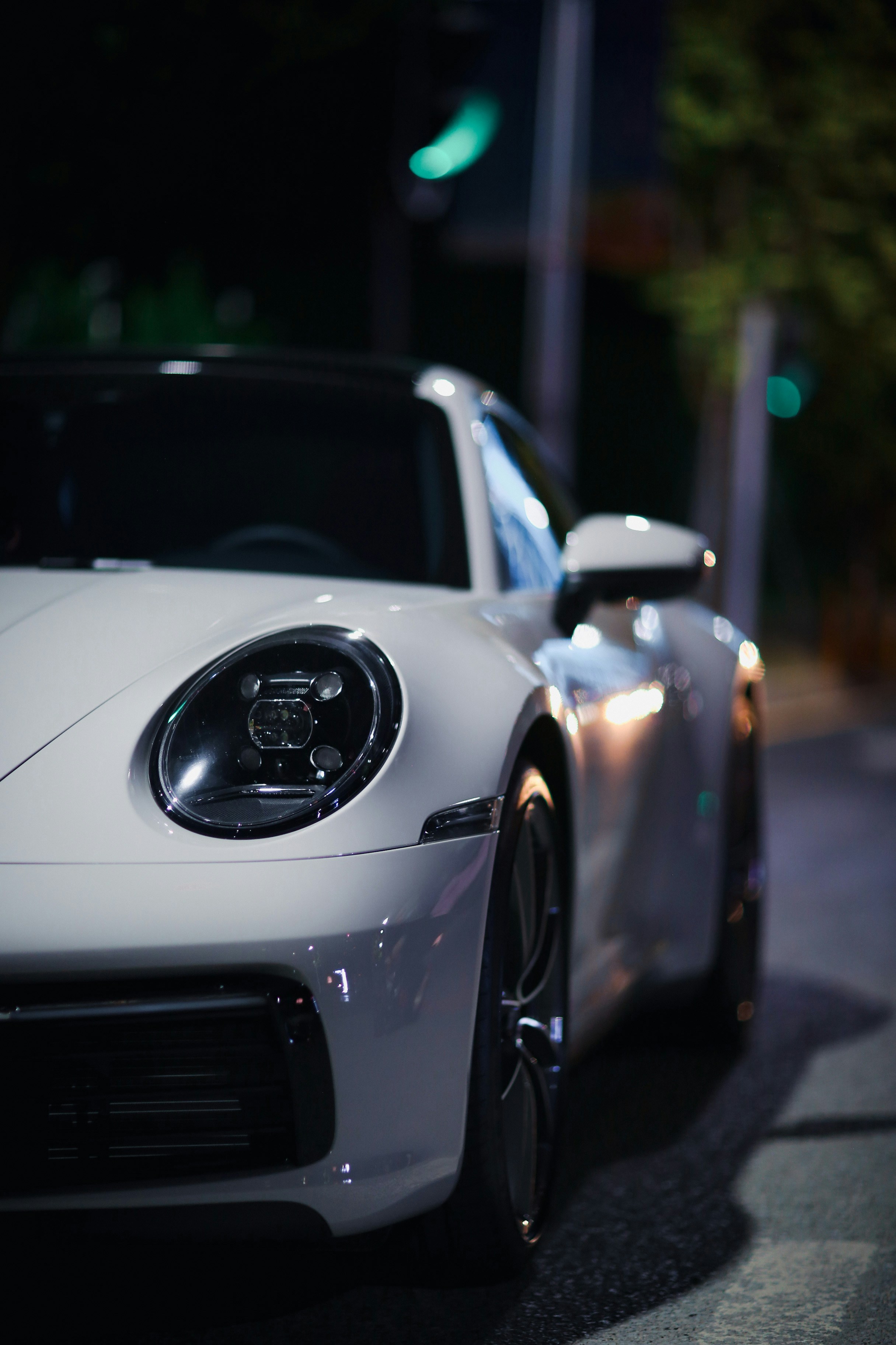 Sleek white sports car parked under streetlights, showcasing its glossy finish and modern design details.
