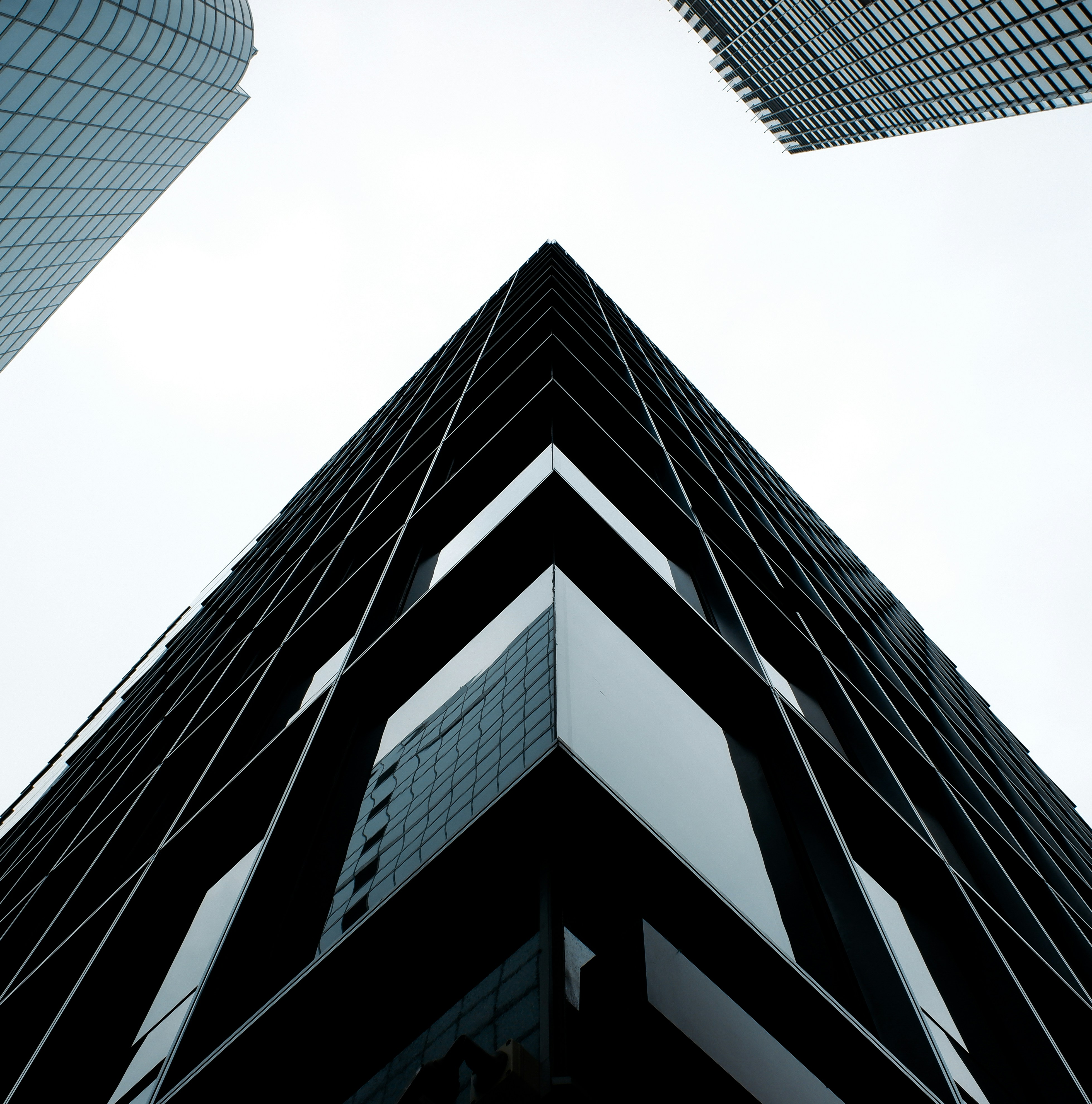 Upward view of a modern skyscraper with sharp geometric lines against a cloudy sky.