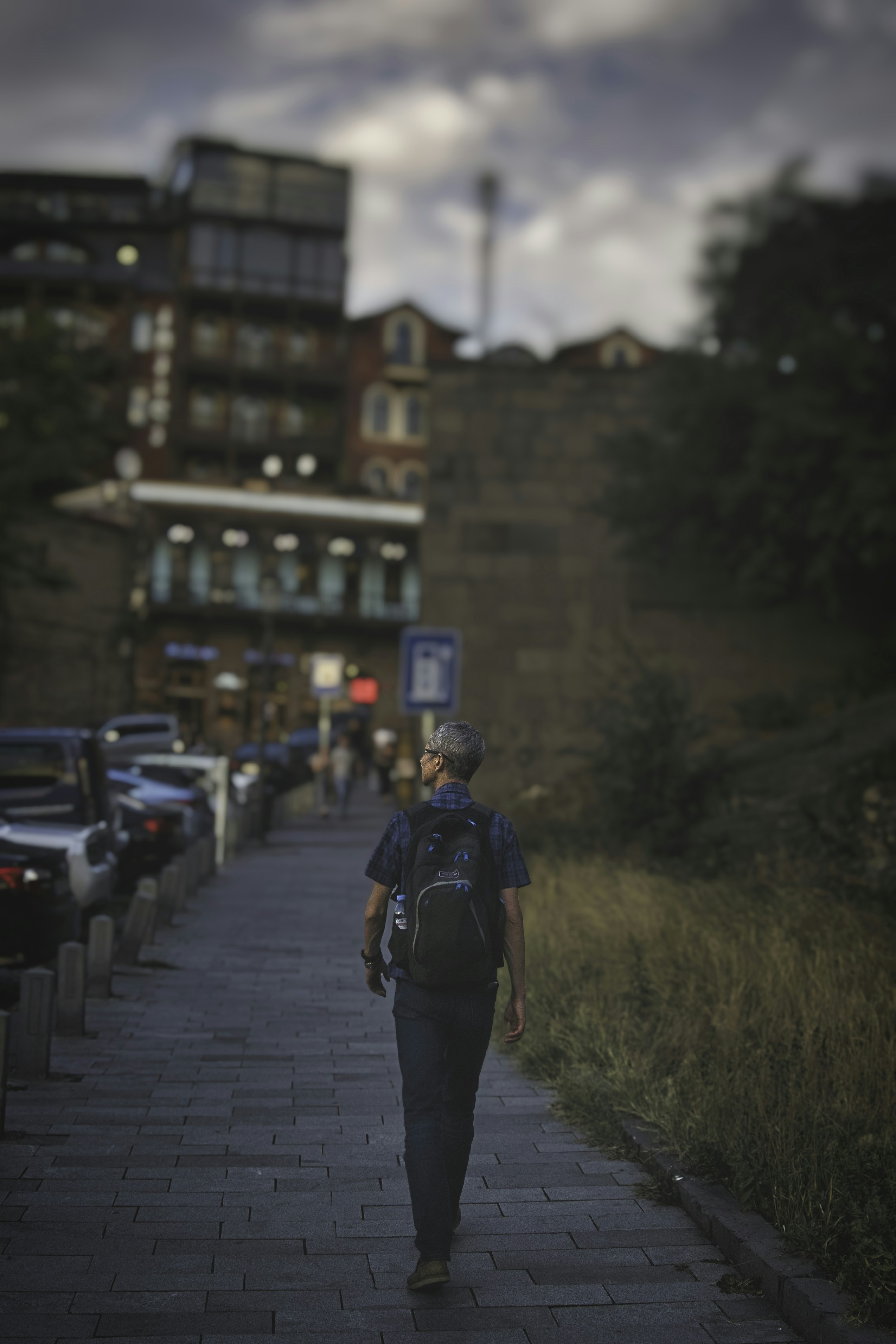 Backpack in the City: A lone wanderer threads a quiet urban sidewalk