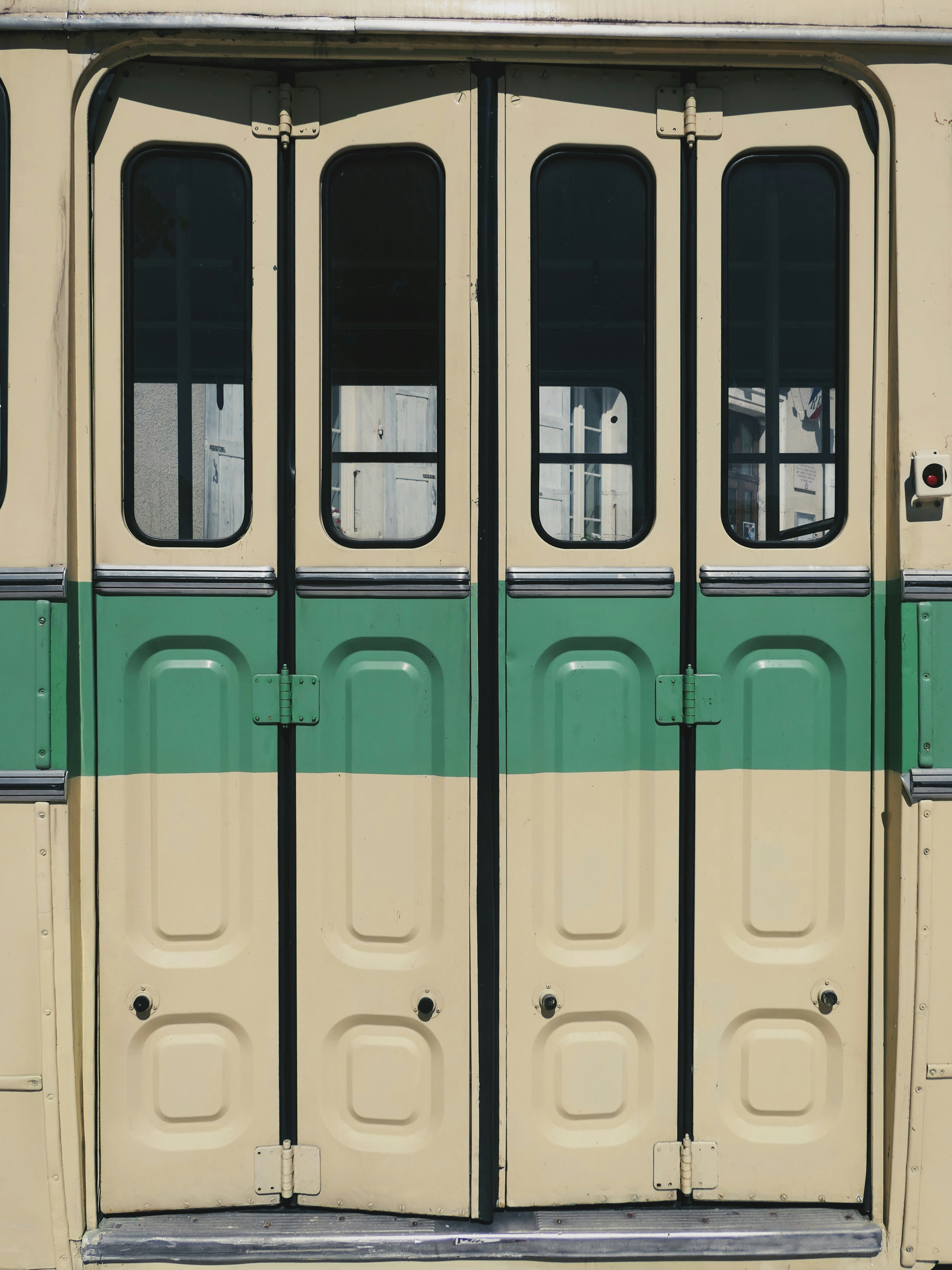 Cream and green vintage transit doors with large glass windows, showcasing a classic design aesthetic. The doors are framed by a contrasting black outline.