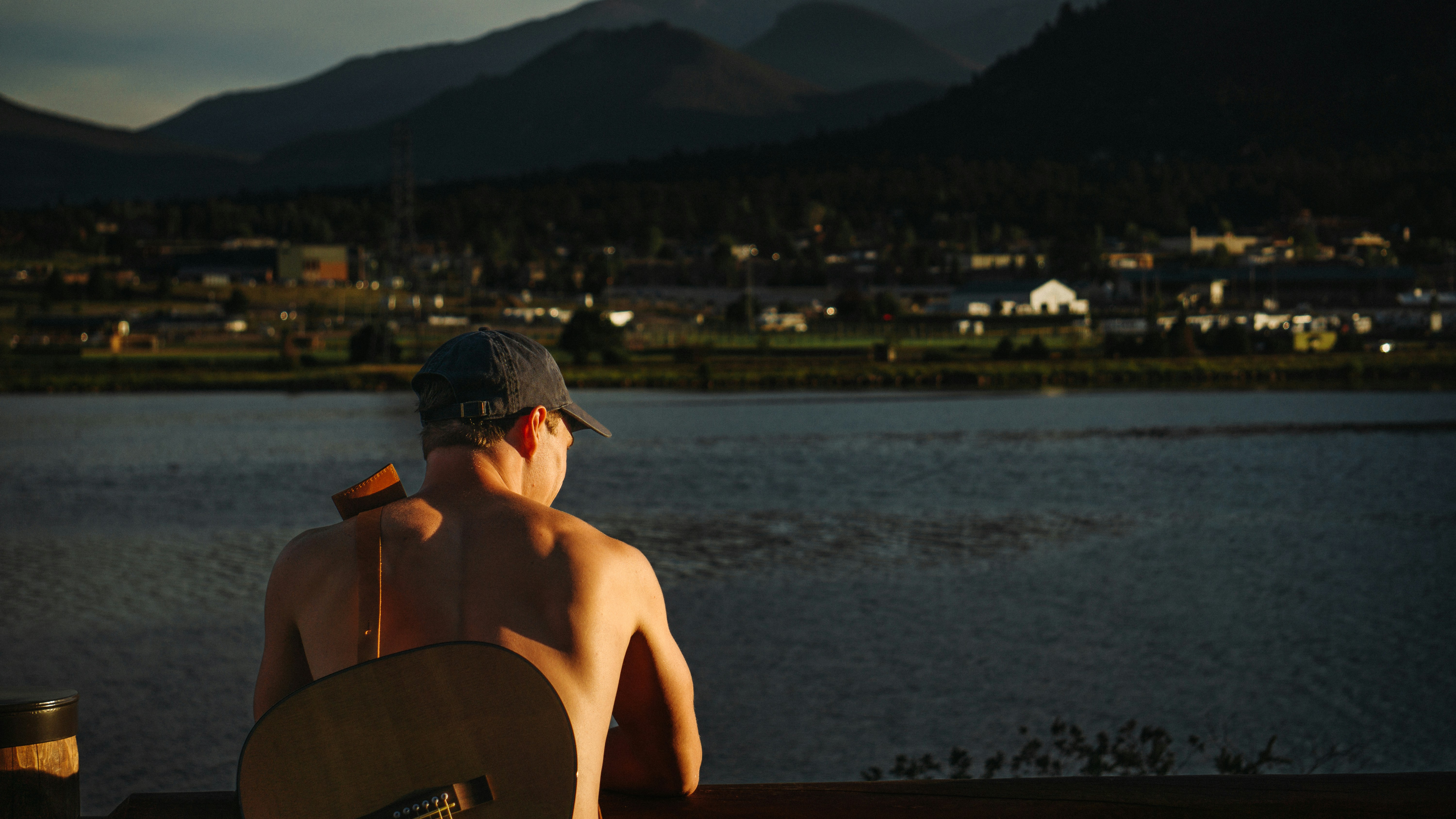 Twilight Strings by the Lake: A Back-Facing Guitarist Beneath Dusked Hills