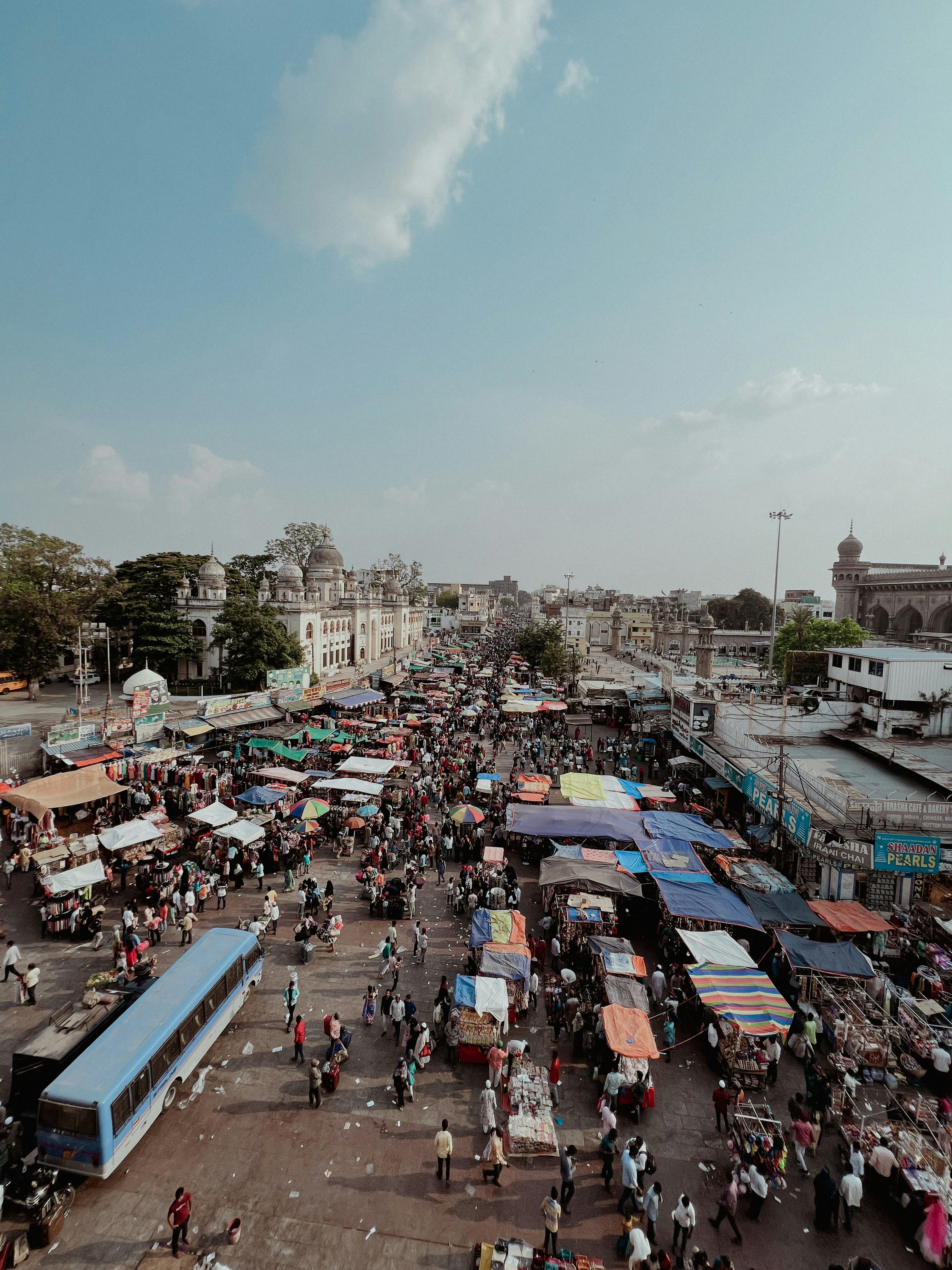 A bustling street market filled with colorful stalls and crowds, showcasing the lively atmosphere of urban commerce. The scene captures the essence of daily life and trade.