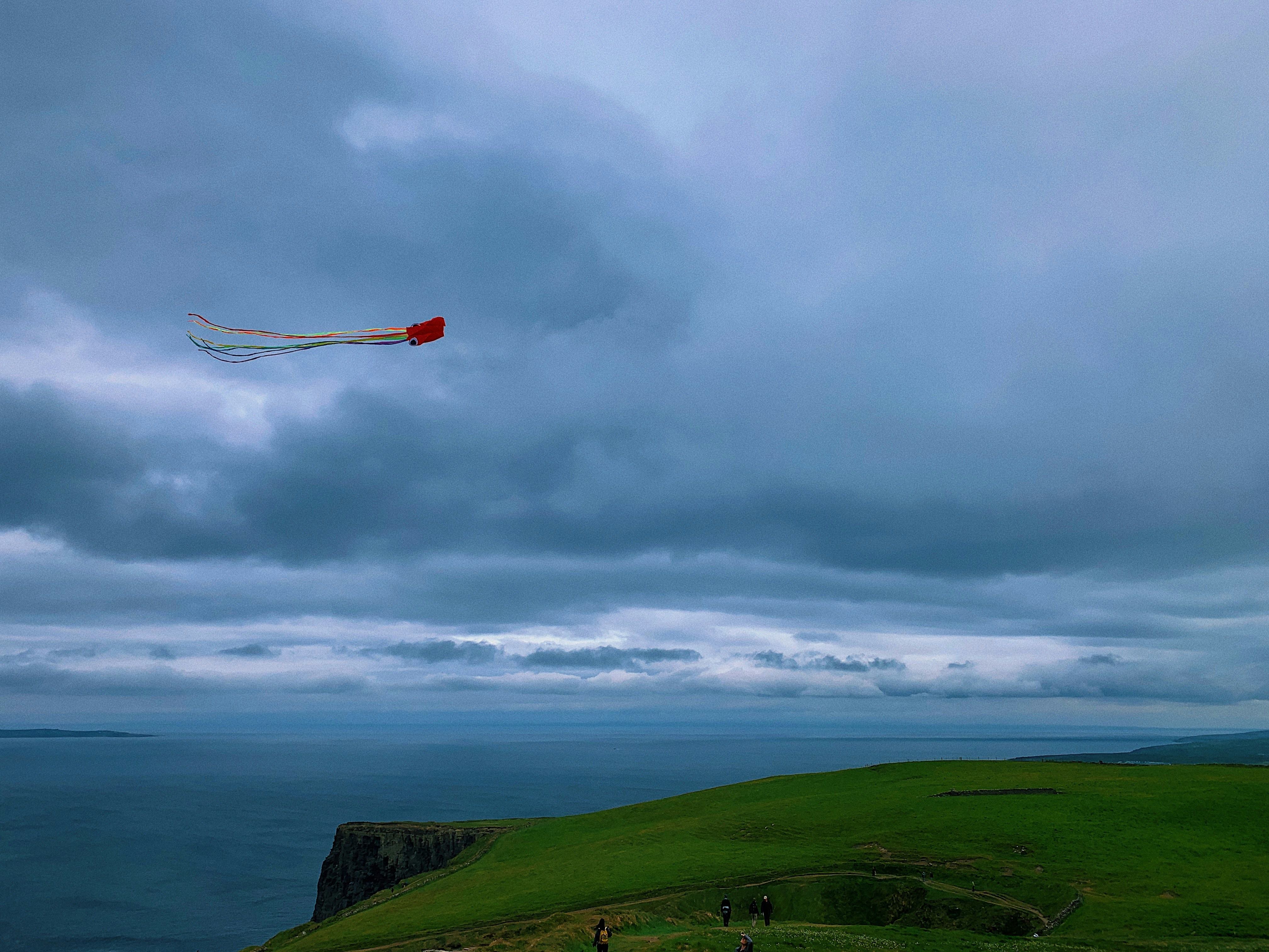 Crimson Kite Over a Wind-Swept Cliffscape