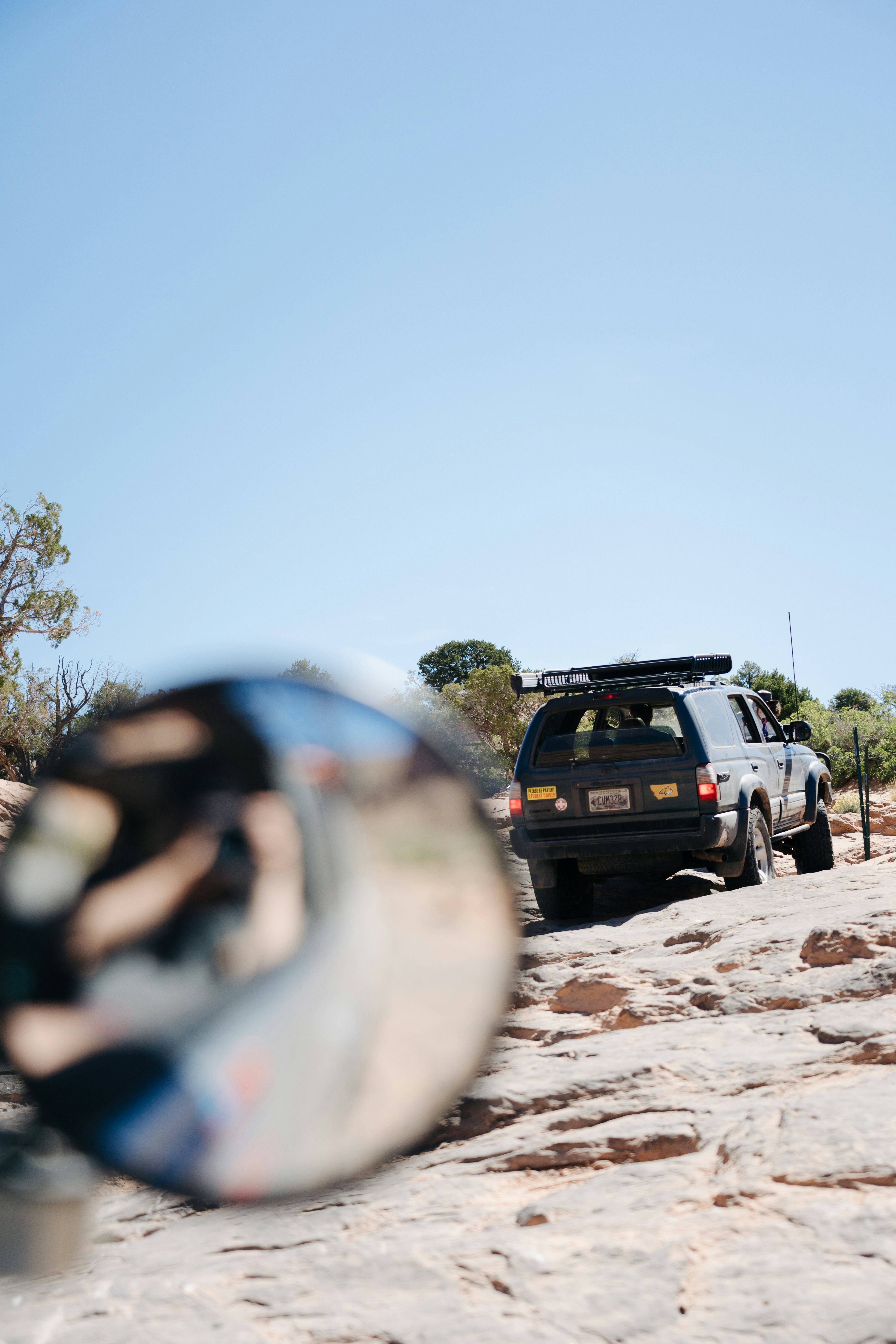 Trail Sentinel: A Blue SUV Conquers the Red Rock Slope