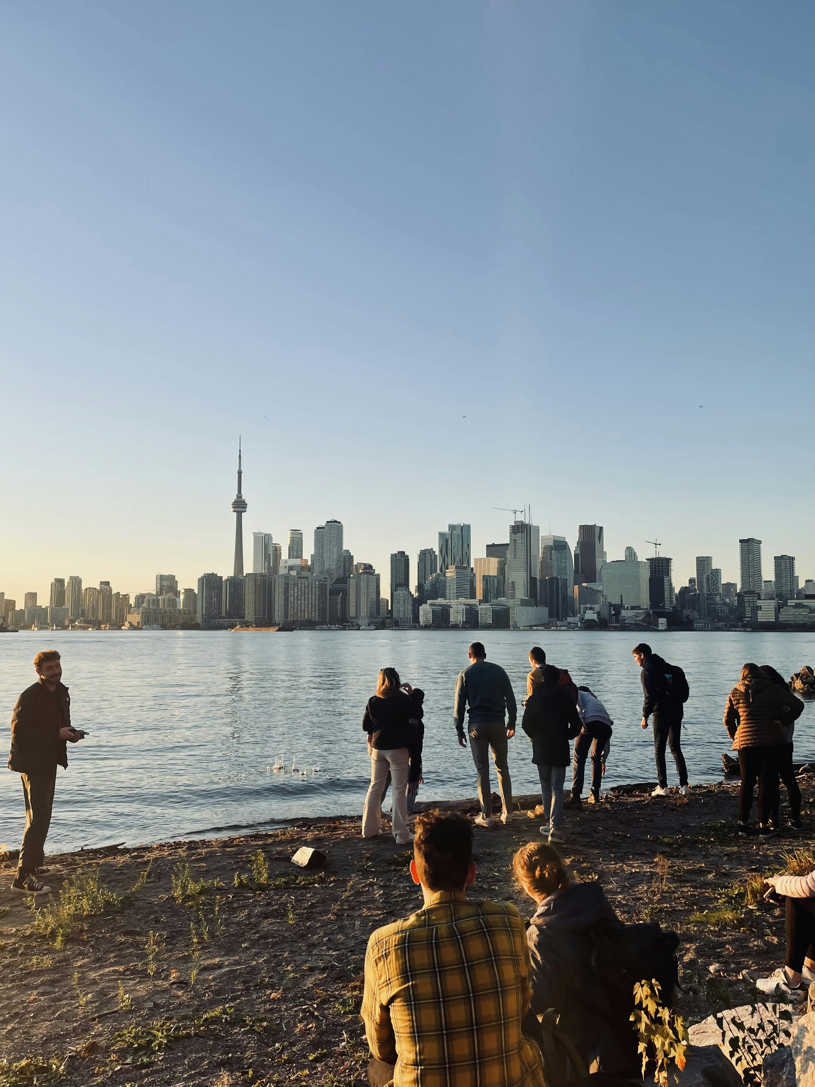 a group of people standing on a beach with a city in the background
