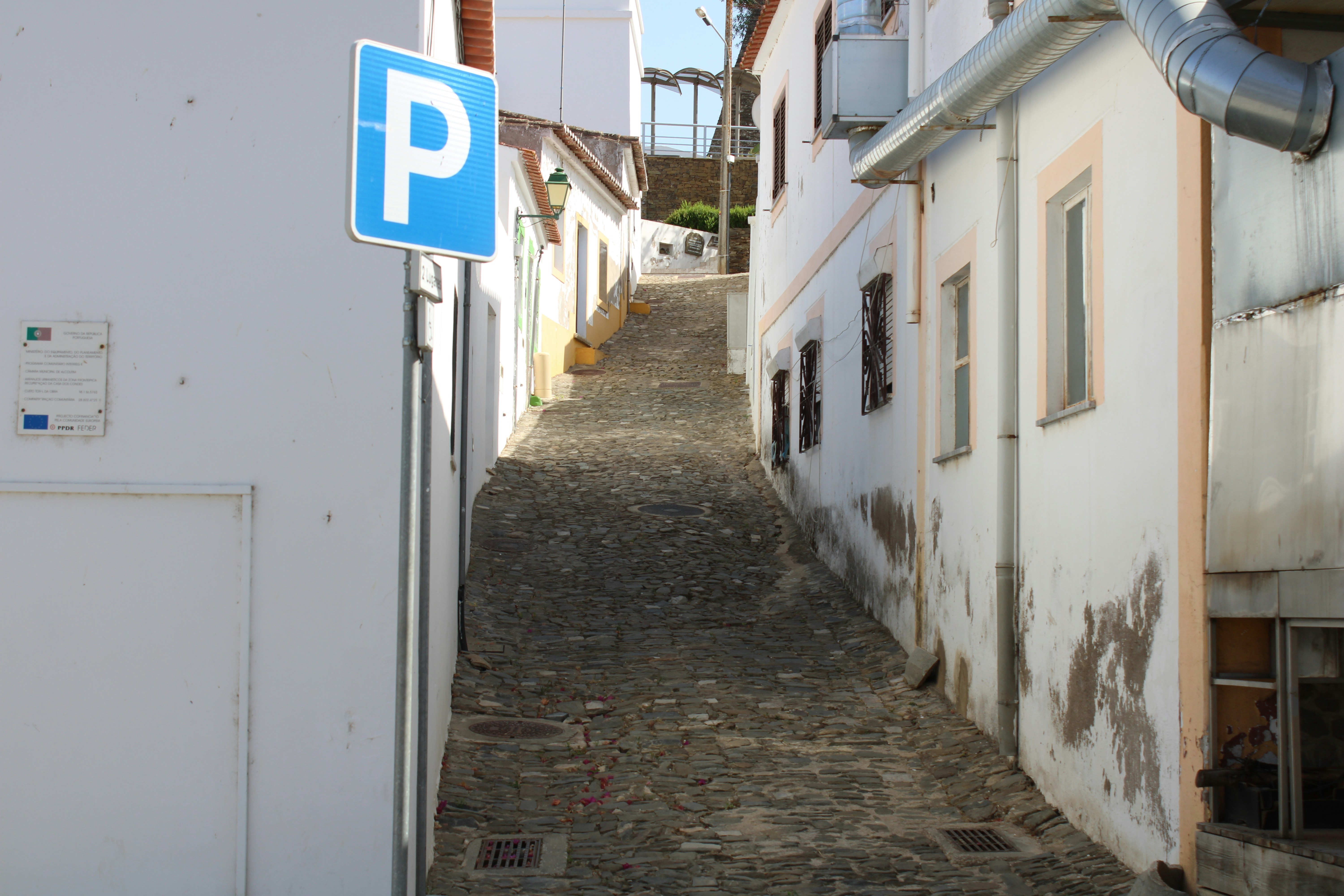 a narrow alley between white buildings