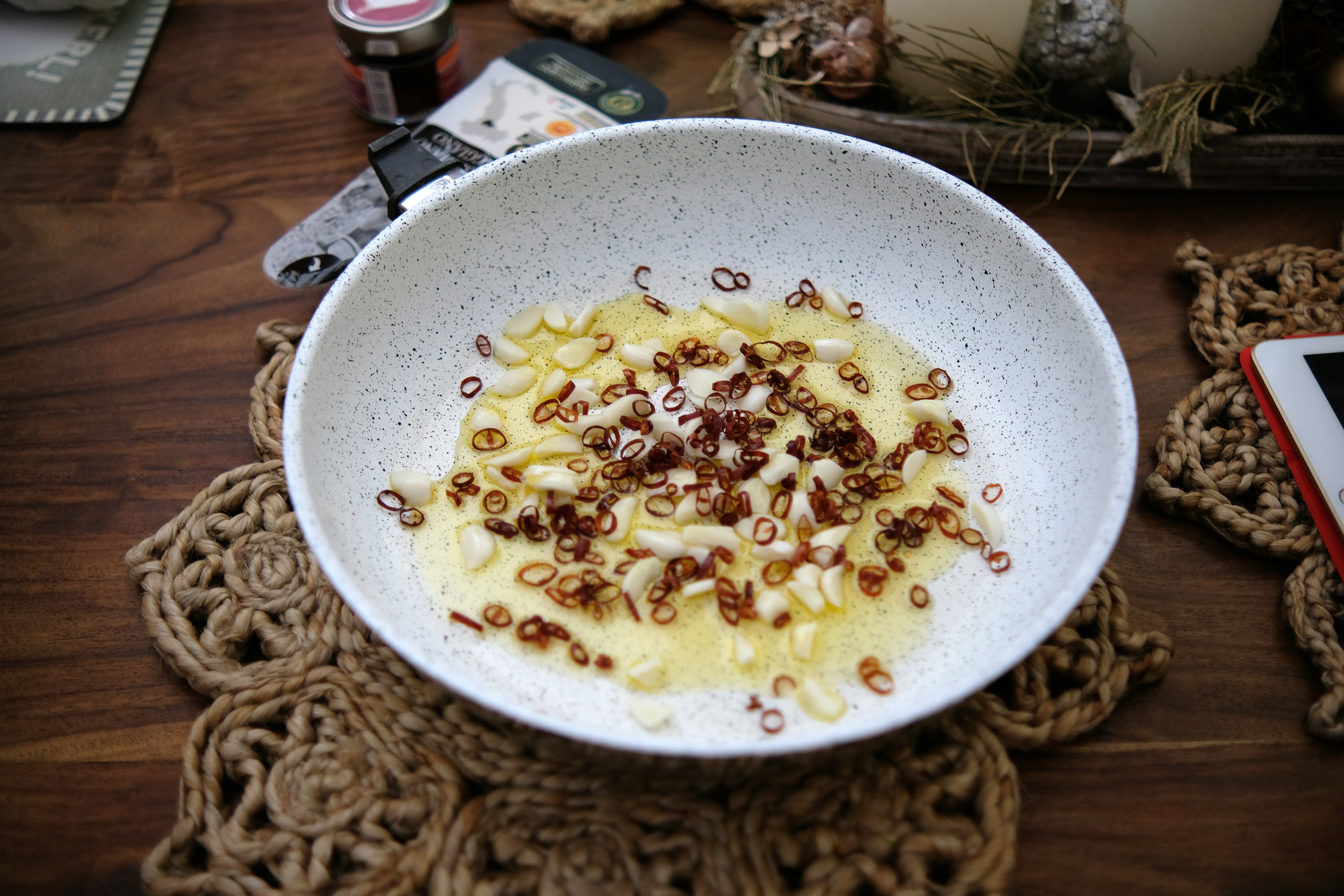 A speckled bowl filled with a mix of golden oil, finely sliced onions, and crispy fried shallots, resting on a textured placemat.