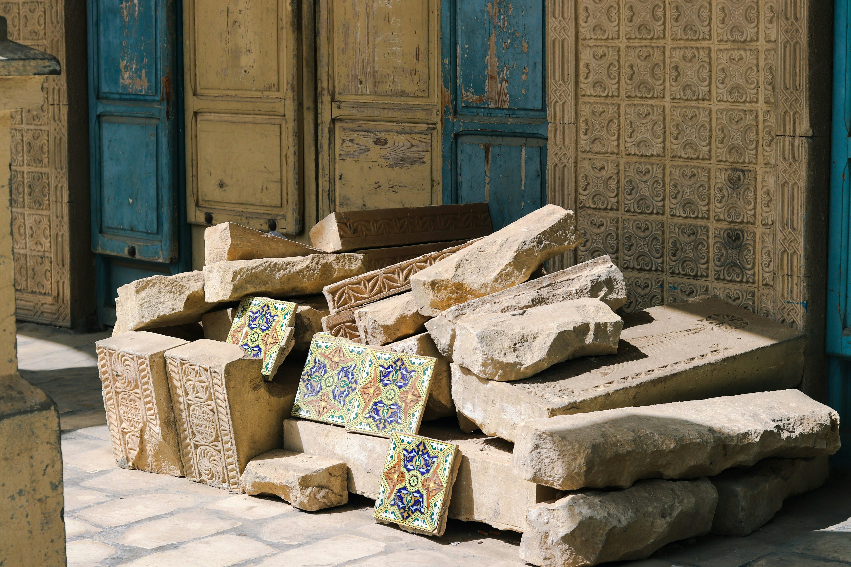 Pile of carved stones and patterned tiles at a weathered doorway