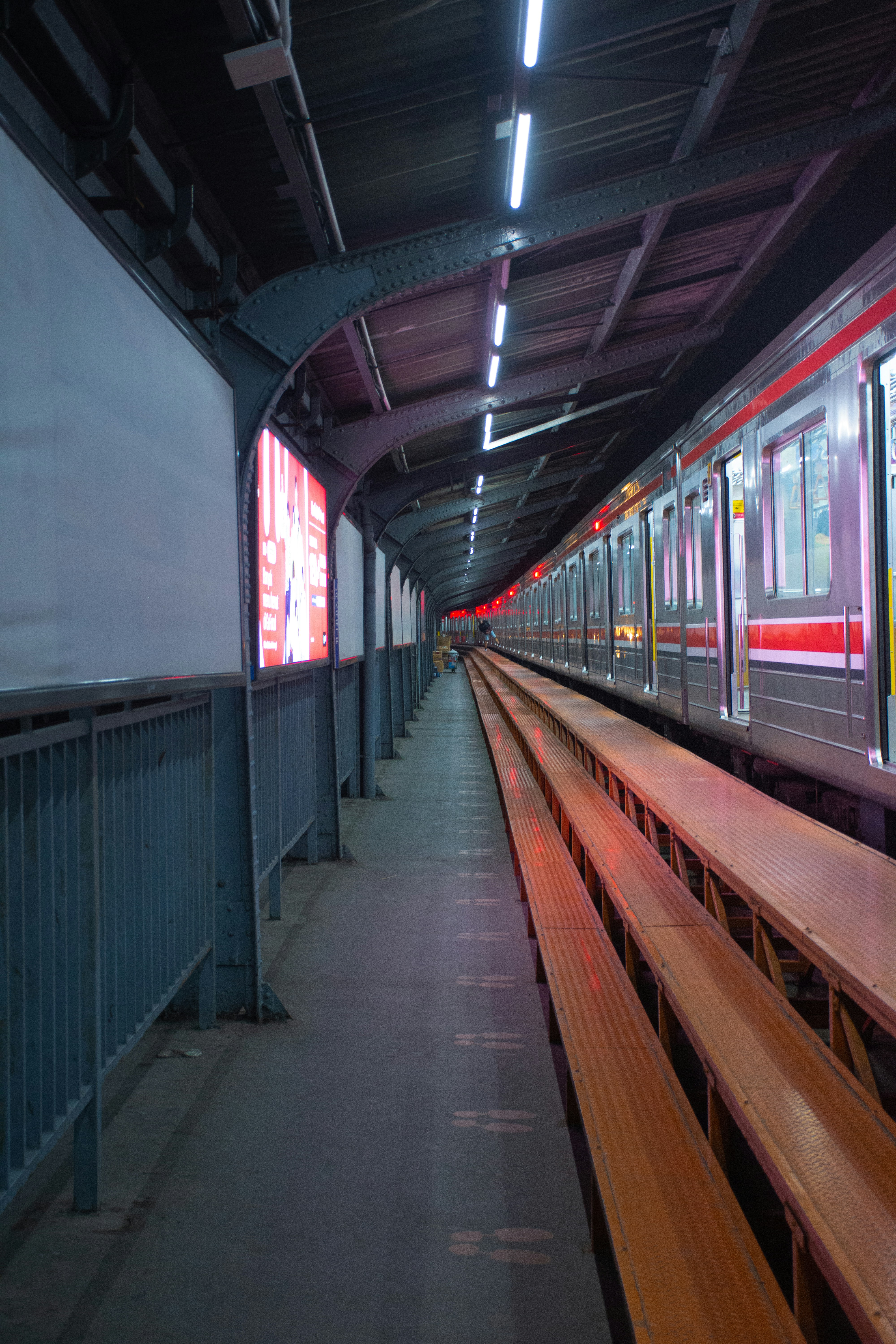 A well-lit subway platform showcasing vibrant advertisements and empty seating areas, emphasizing the stillness of urban transit.