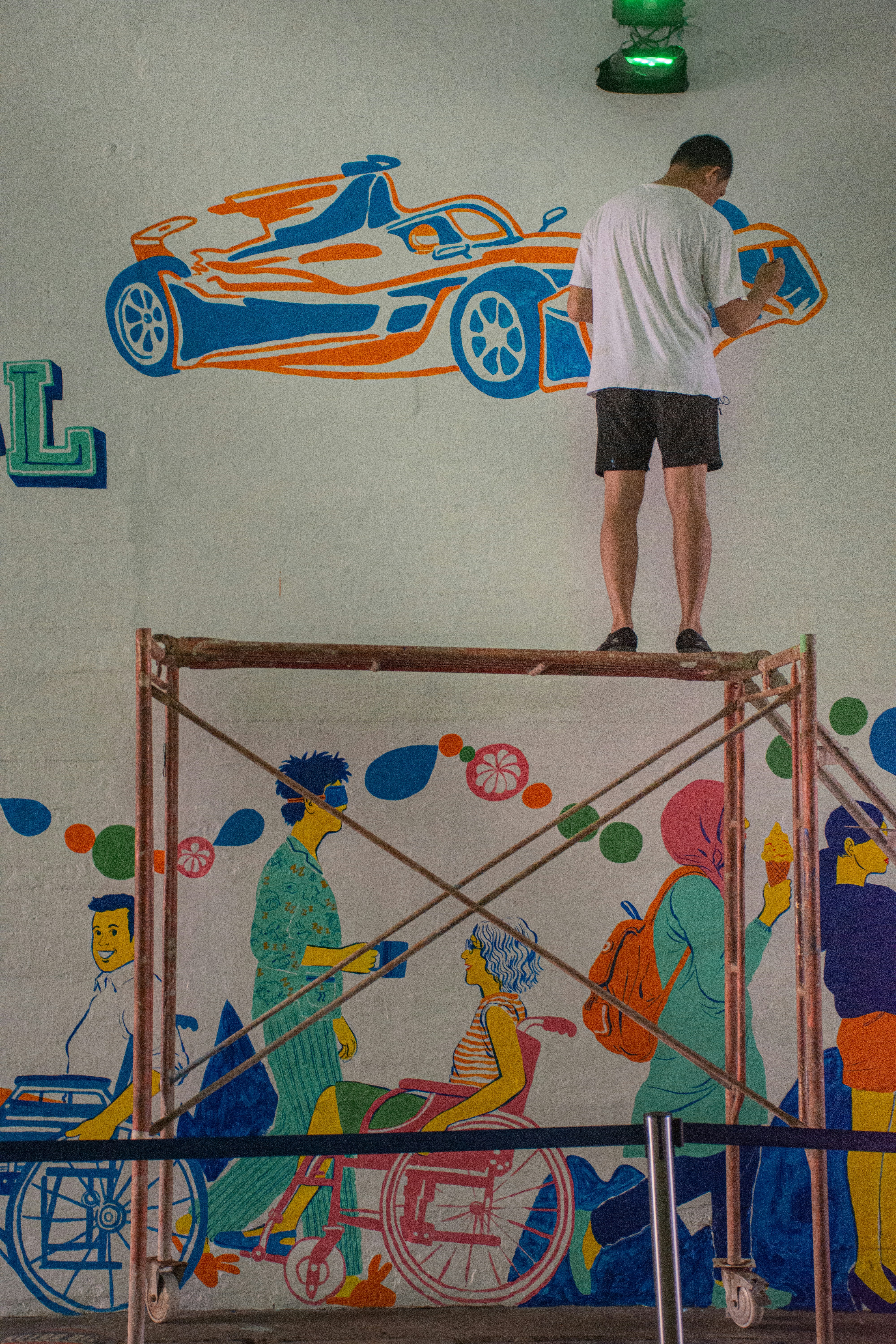 Suspended Artist: Scaffolded Focus Under a Neon Car Mural