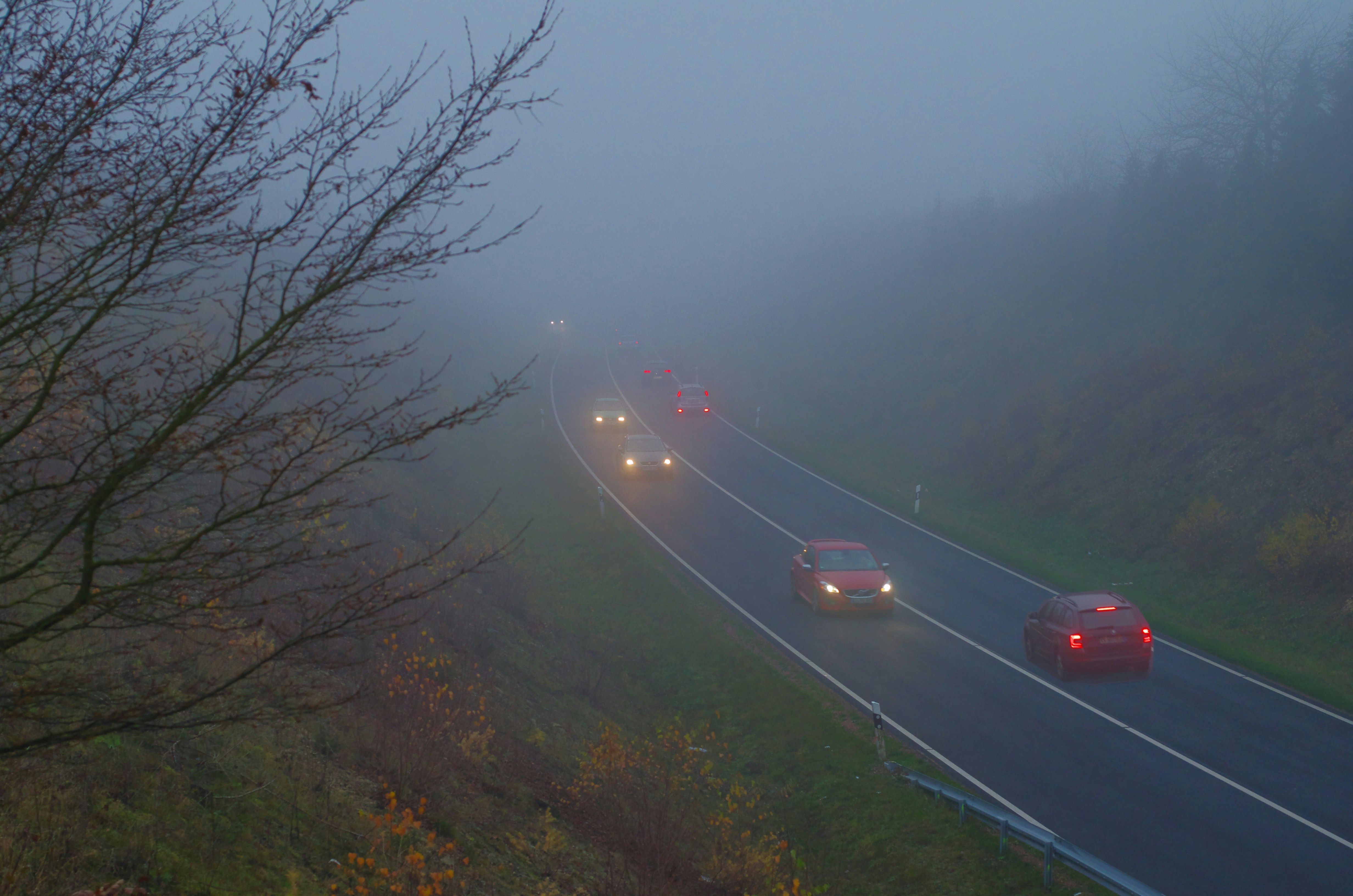 Fogbound Curve: Tail Lights Carve a Quiet Highway