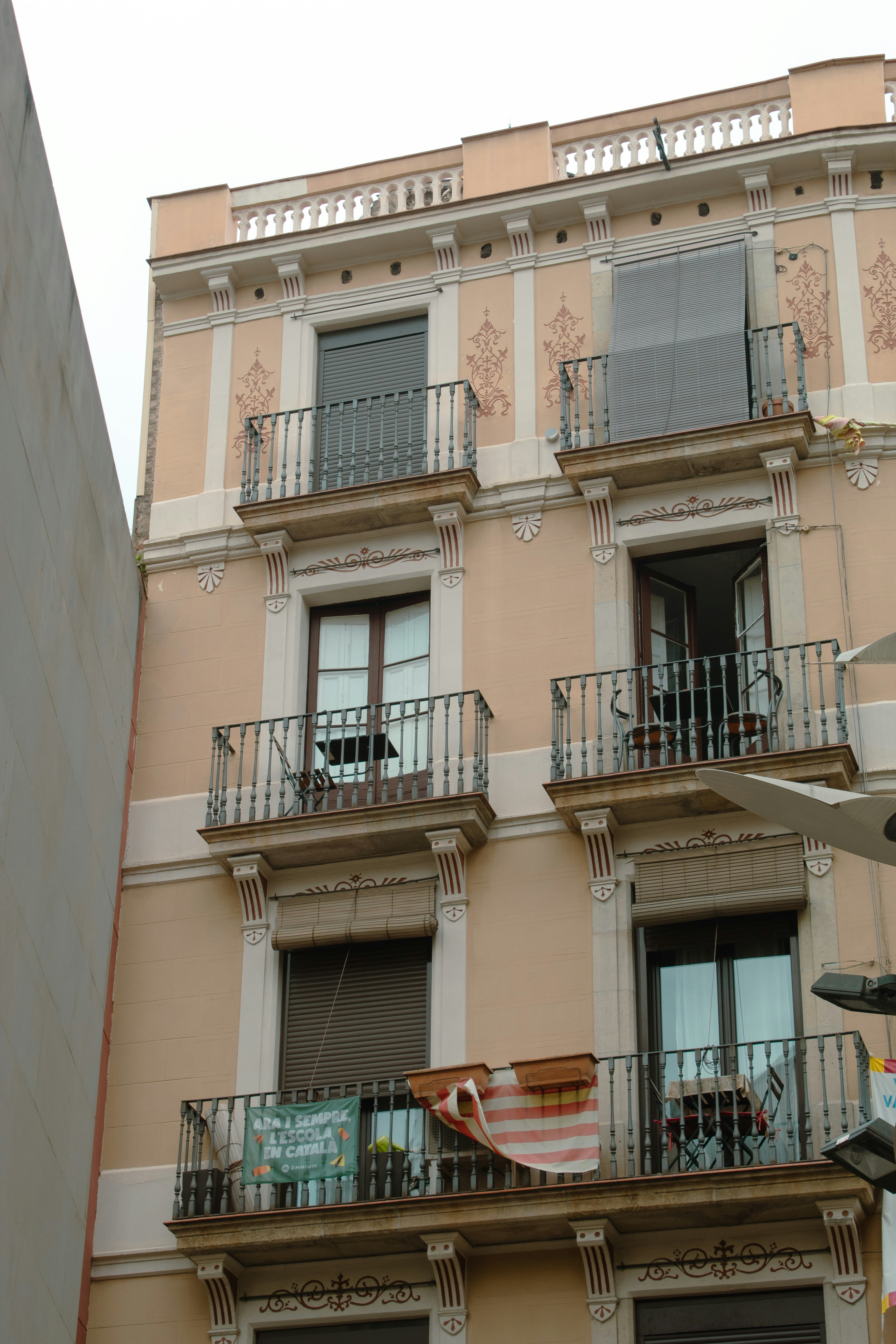 Elegant balconies adorned with decorative details on a historic building in Barcelona, showcasing vibrant textiles and a glimpse of daily life.