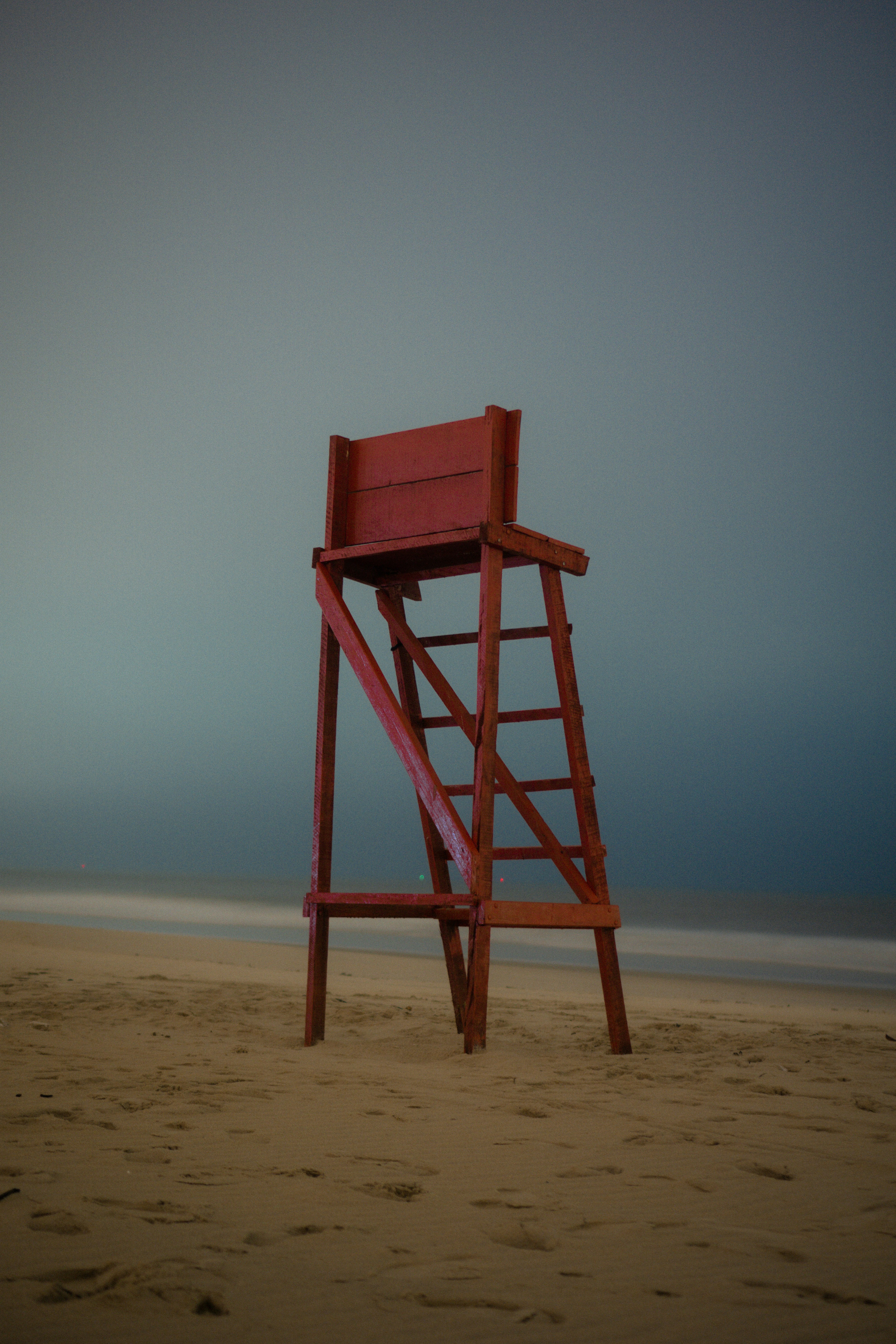 Crimson Lifeguard Chair on a Quiet Beach at Dusk