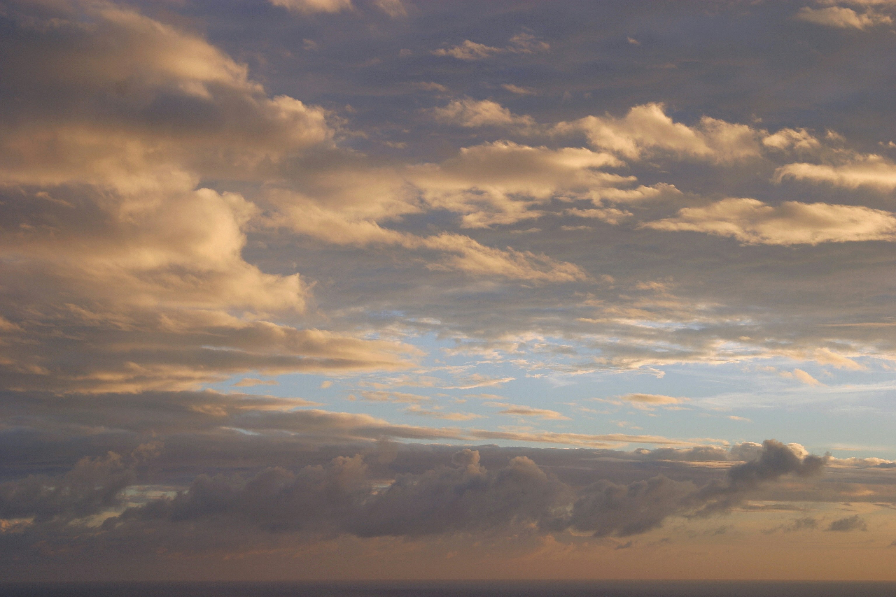 A serene expanse of clouds painted in soft hues at twilight, capturing the transition from day to night.
