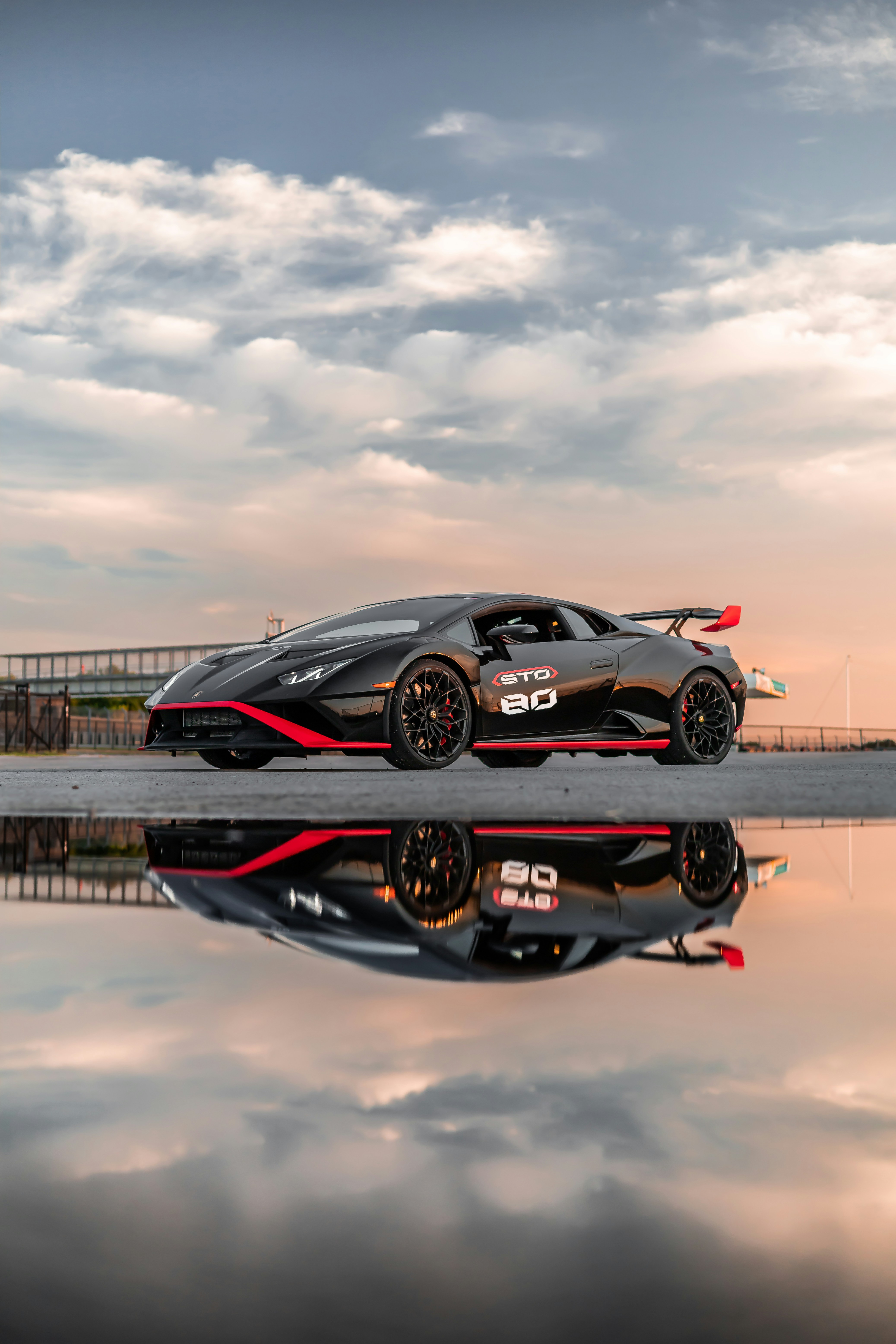 Glassbound Velocity: A black hypercar mirrored on a sunset-glazed puddle