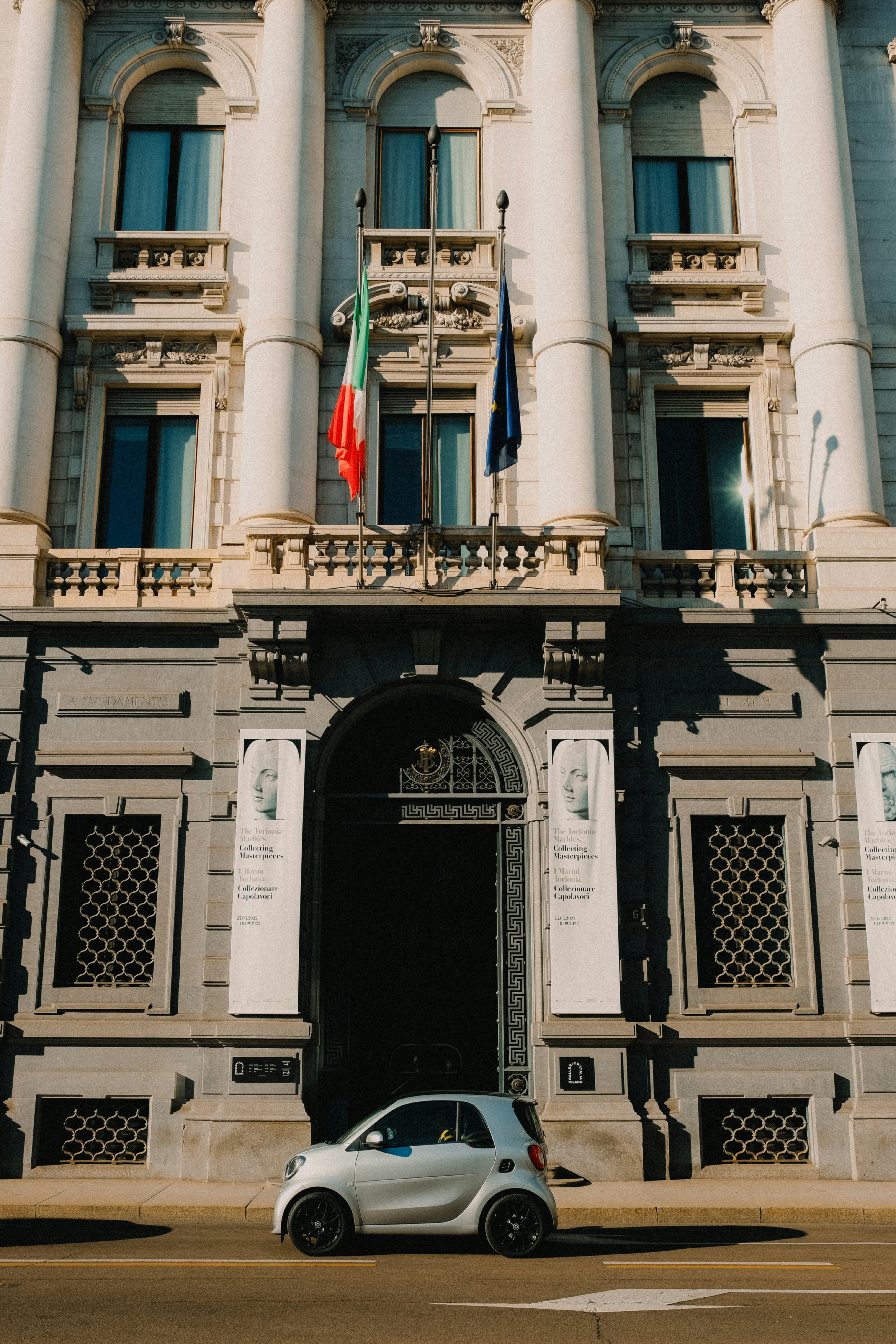 A car parked in front of a building with columns and a flag photo ...