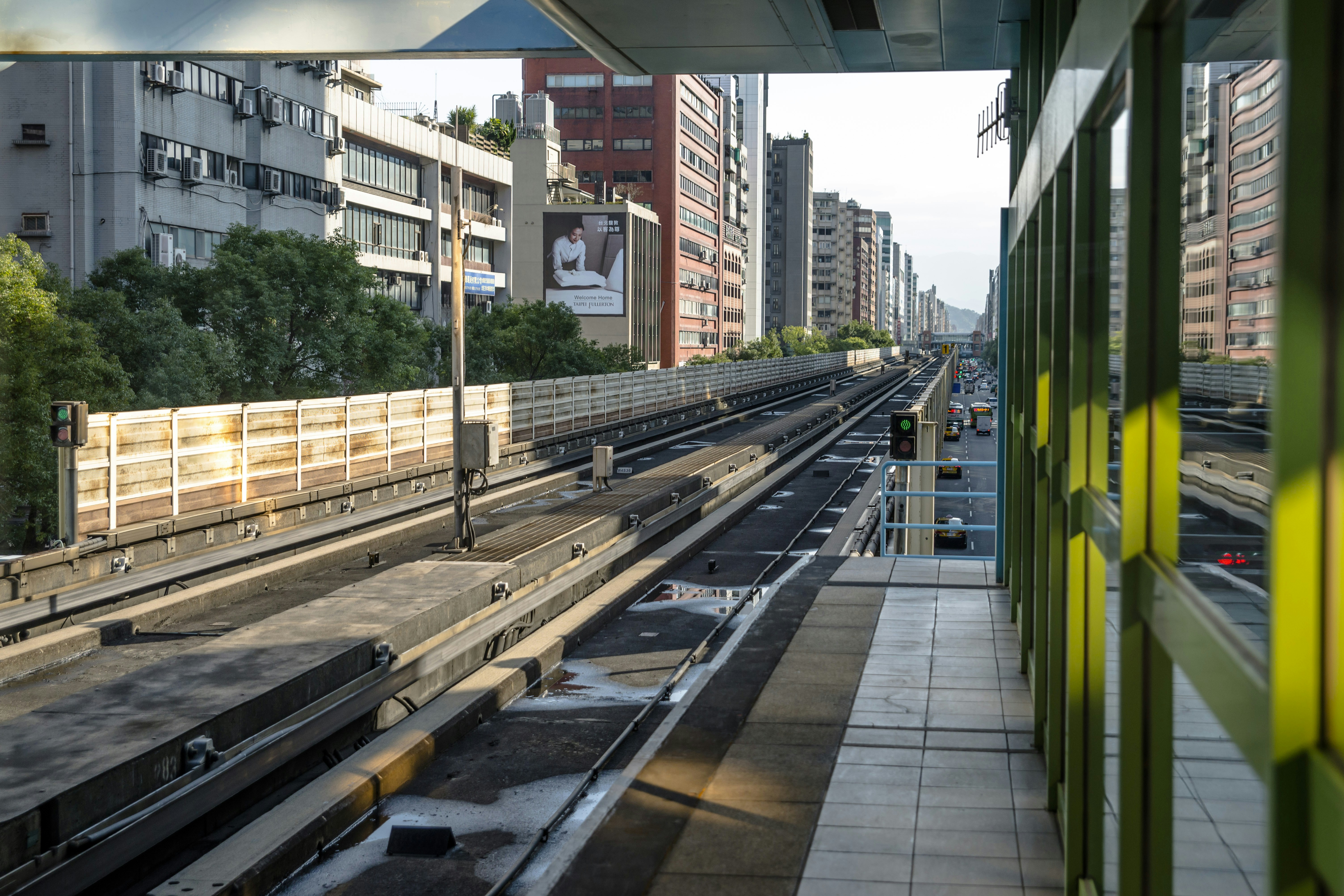 Rails Recede Through a Glass-Green Transit Corridor toward a City Horizon