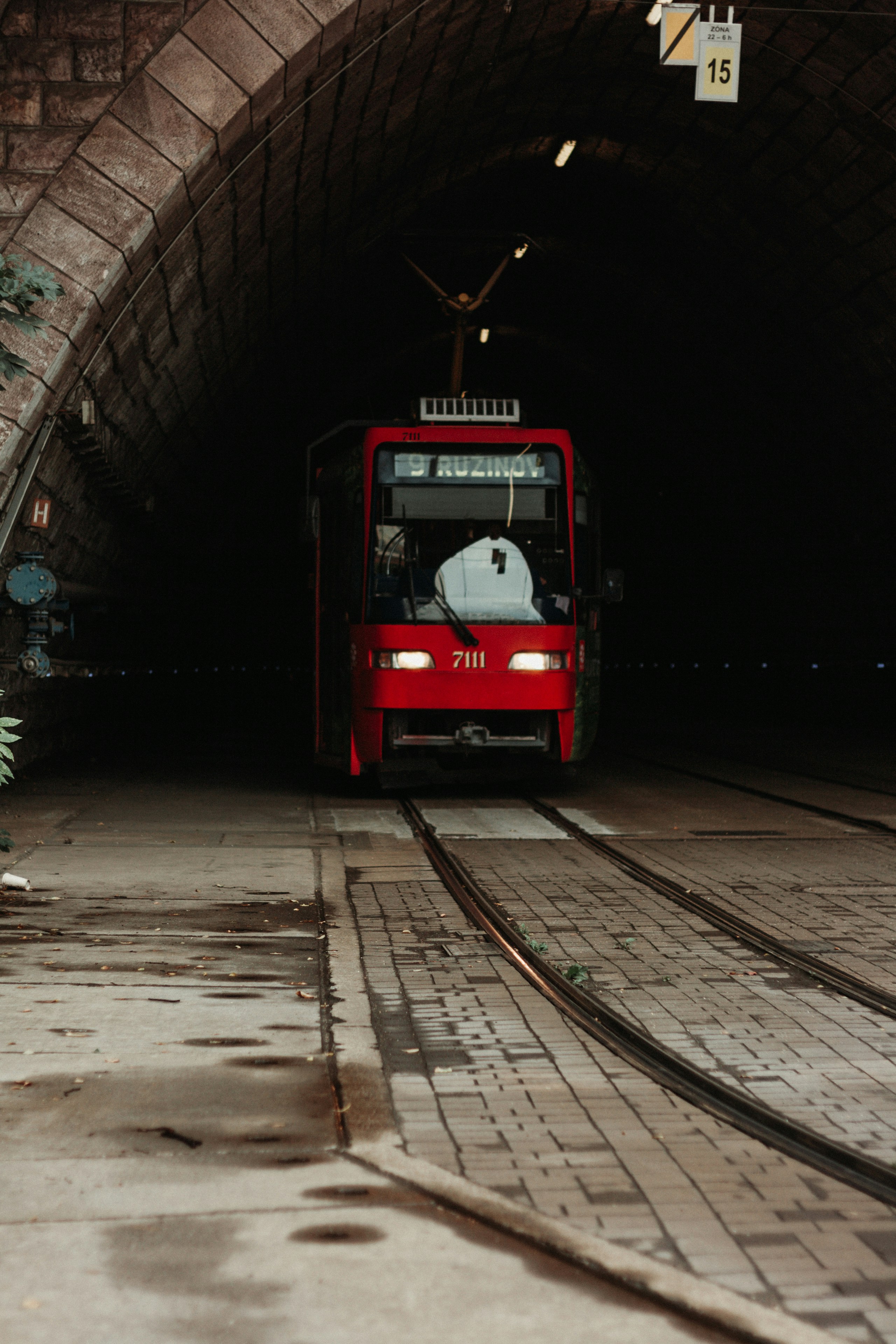 Red Tram Breaks into Light from a Dim Stone Tunnel