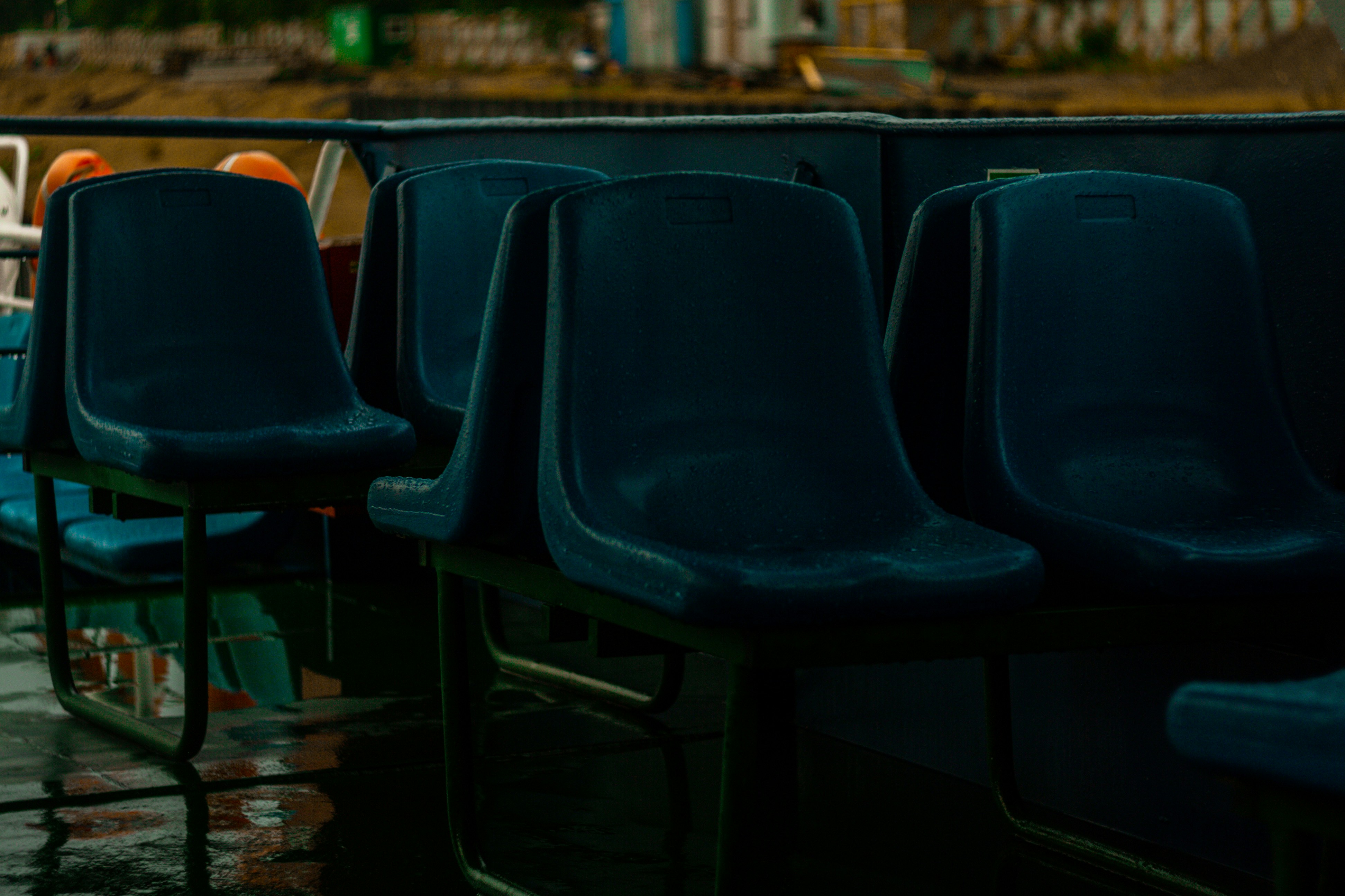 Empty blue plastic seats on a boat, reflecting a sense of stillness and solitude. The scene captures a moment of quiet amidst a bustling environment.
