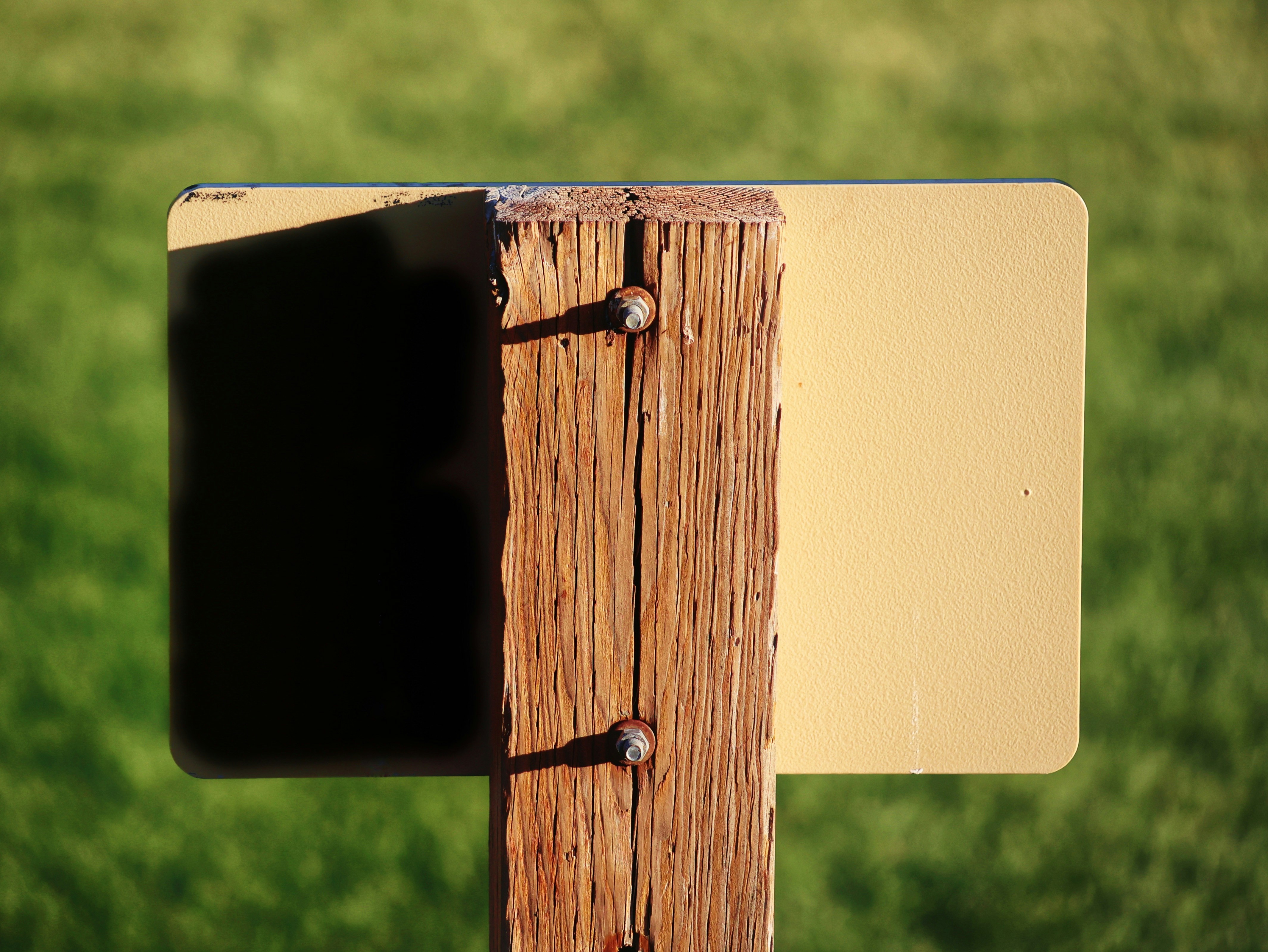 Weathered Wood and Painted Panel: A Close-Up on a Rustic Post with Soft Green Backdrop