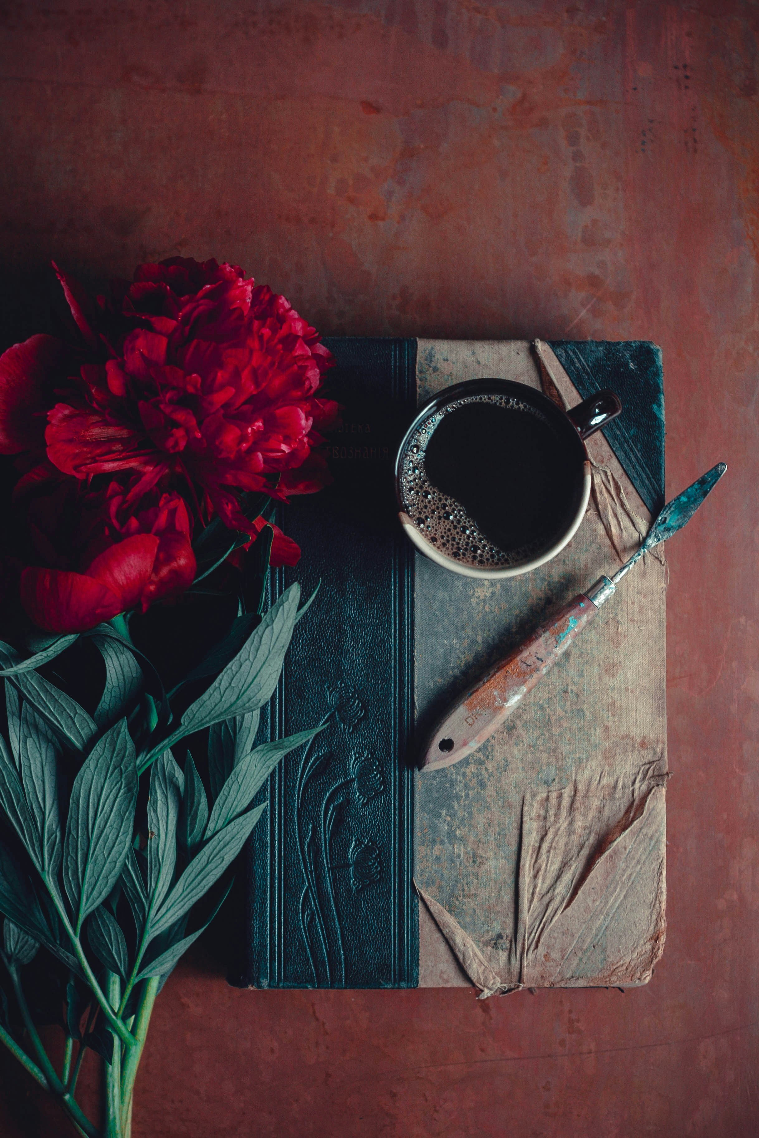 Red Peony, Inked Journal, and Coffee on a Weathered Desk