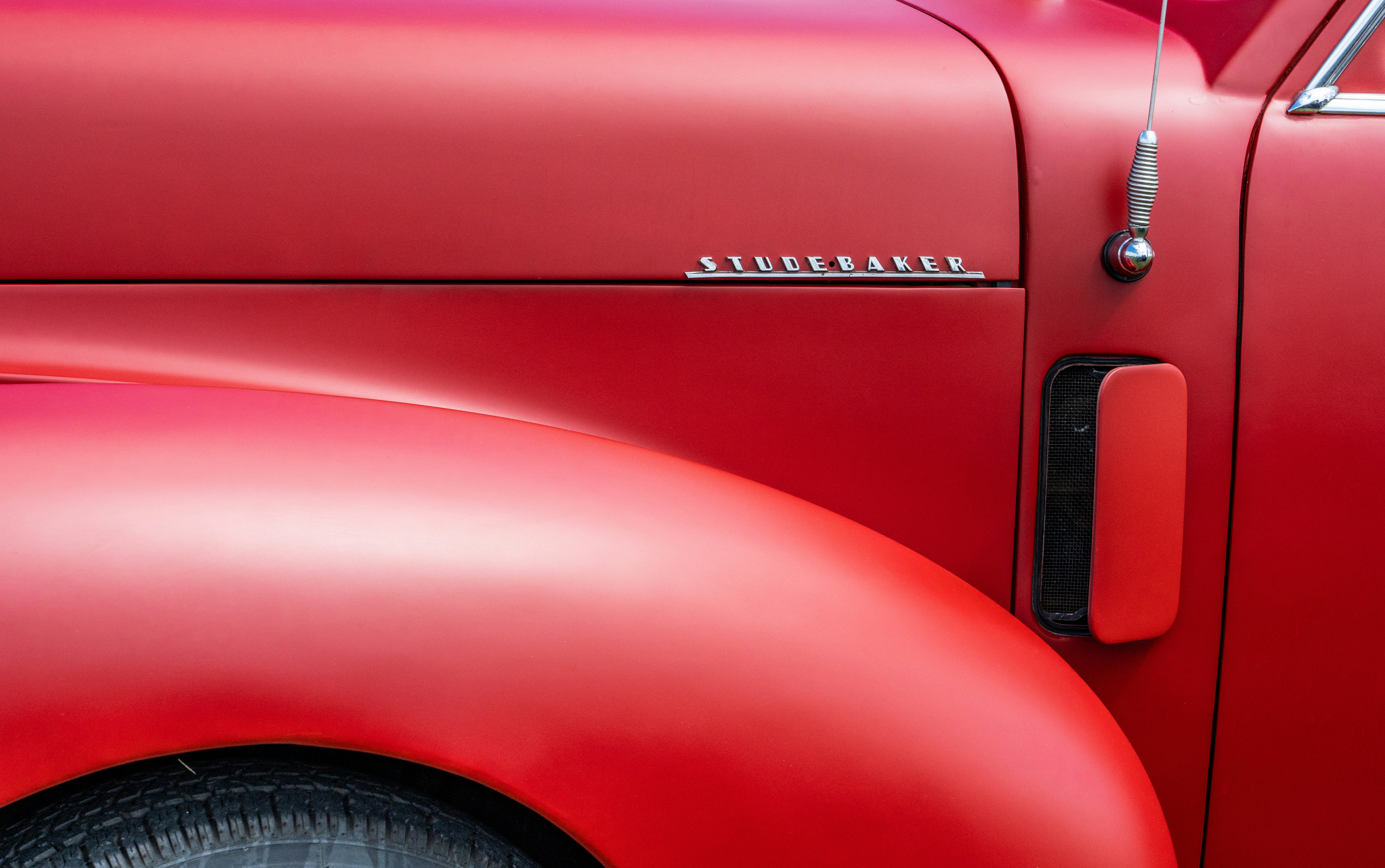 Close-up of a vintage Studebaker truck showcasing its sleek red finish and distinctive branding.