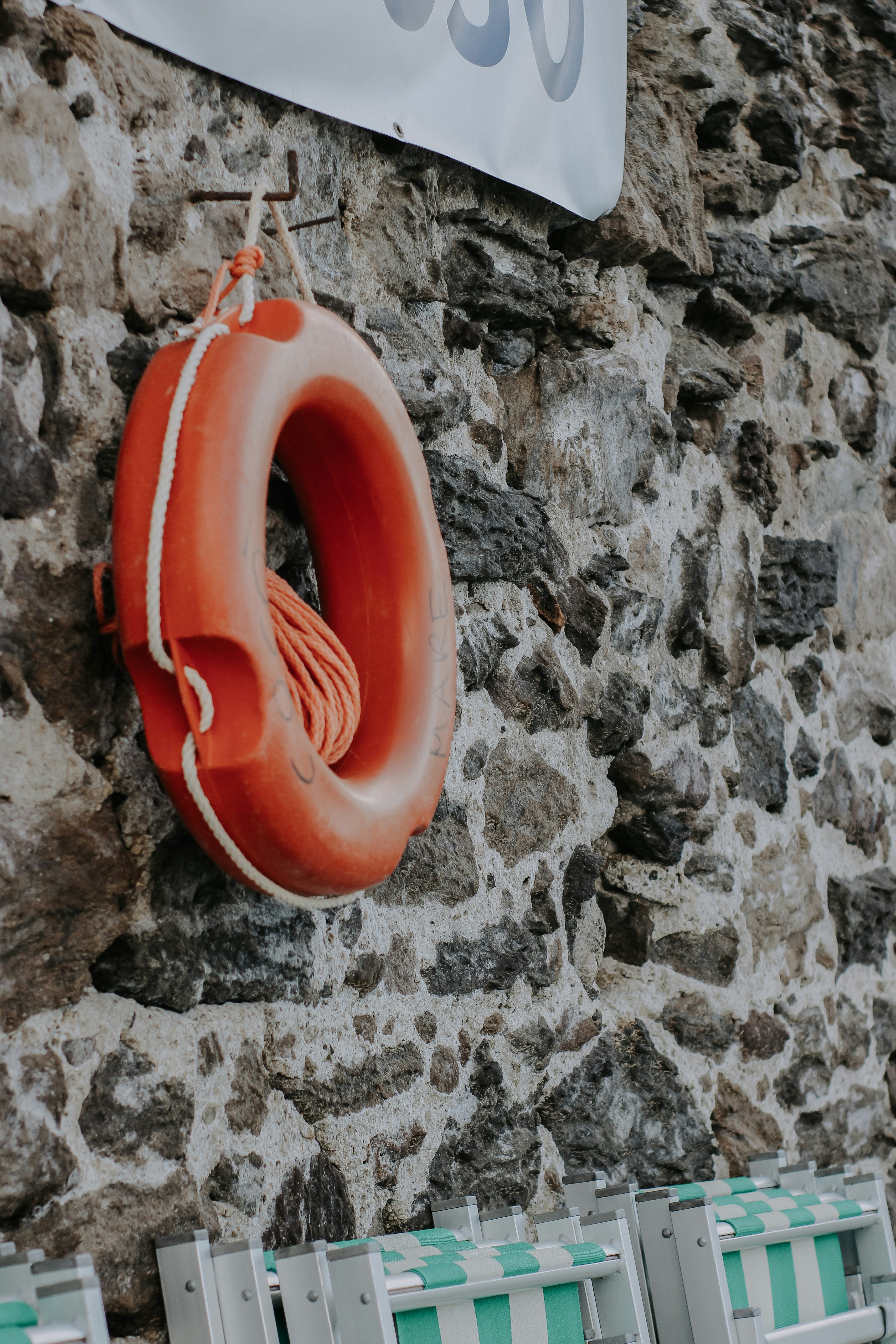 Orange Lifebuoy Anchored to a Rugged Stone Facade