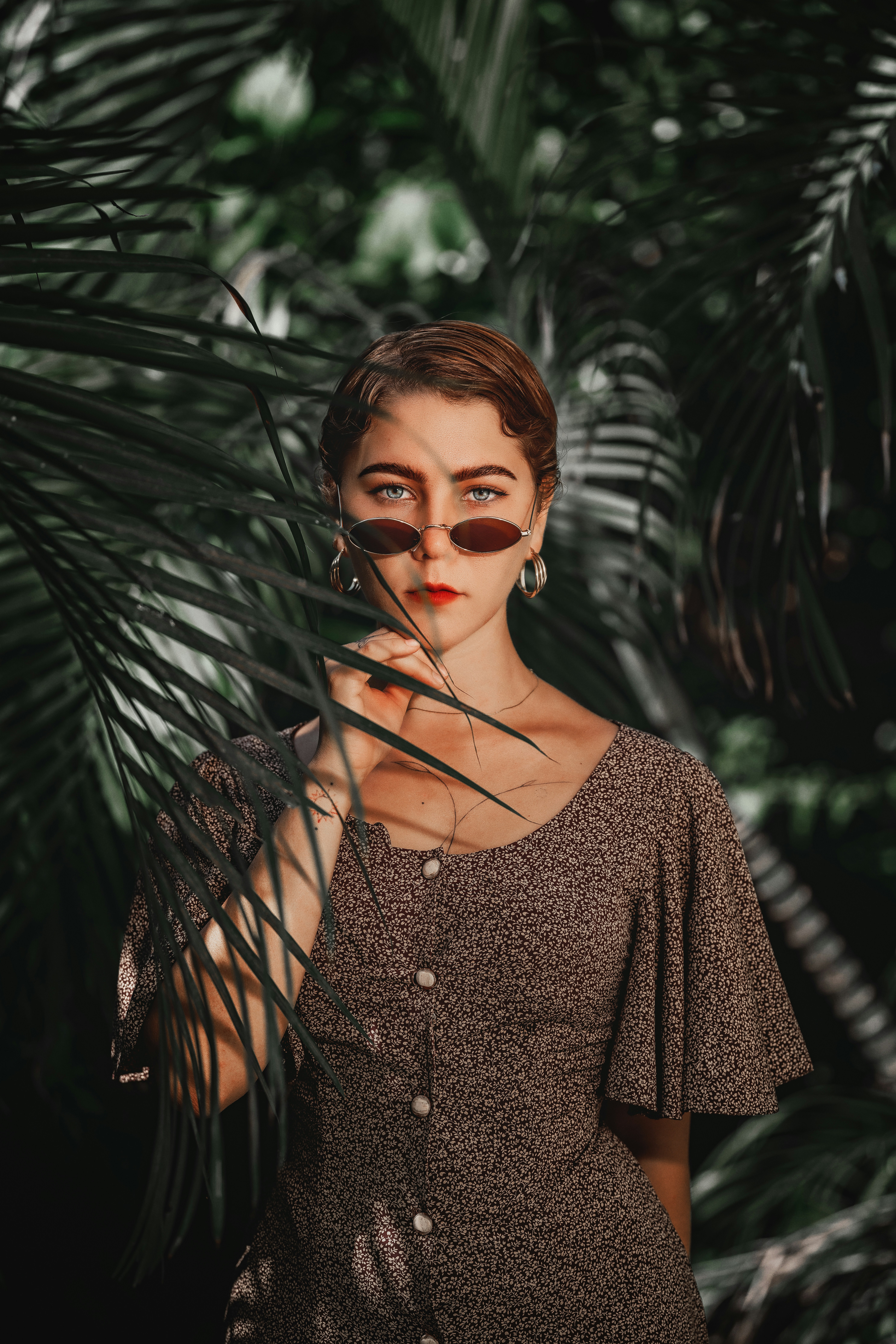 A portrait of a woman in between green plants in the jungle 