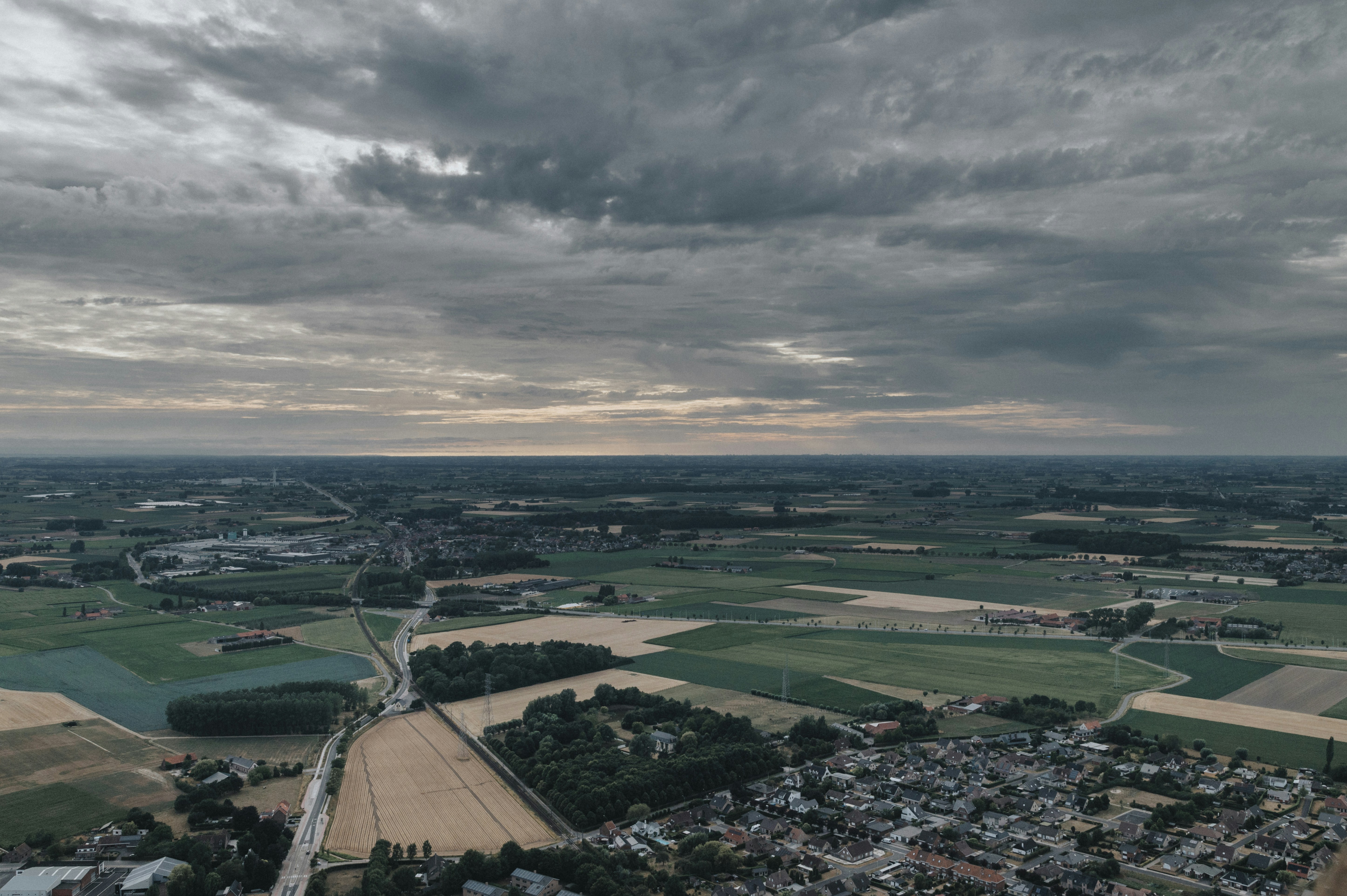 Aerial Canvas: Farmlands Meet Suburbia Under a Storm-tinged Sky