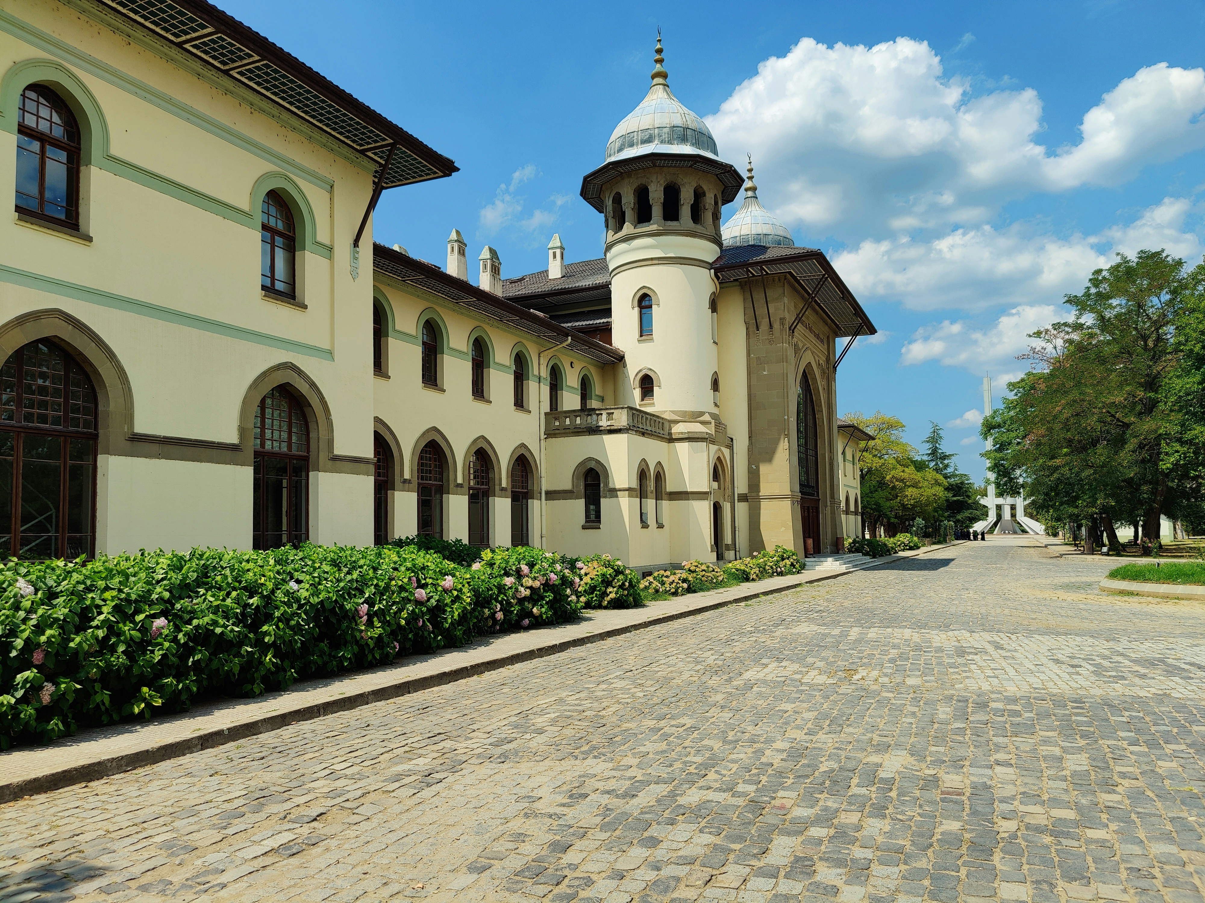Historic building with arched windows and a prominent tower set against a vibrant blue sky with fluffy clouds.