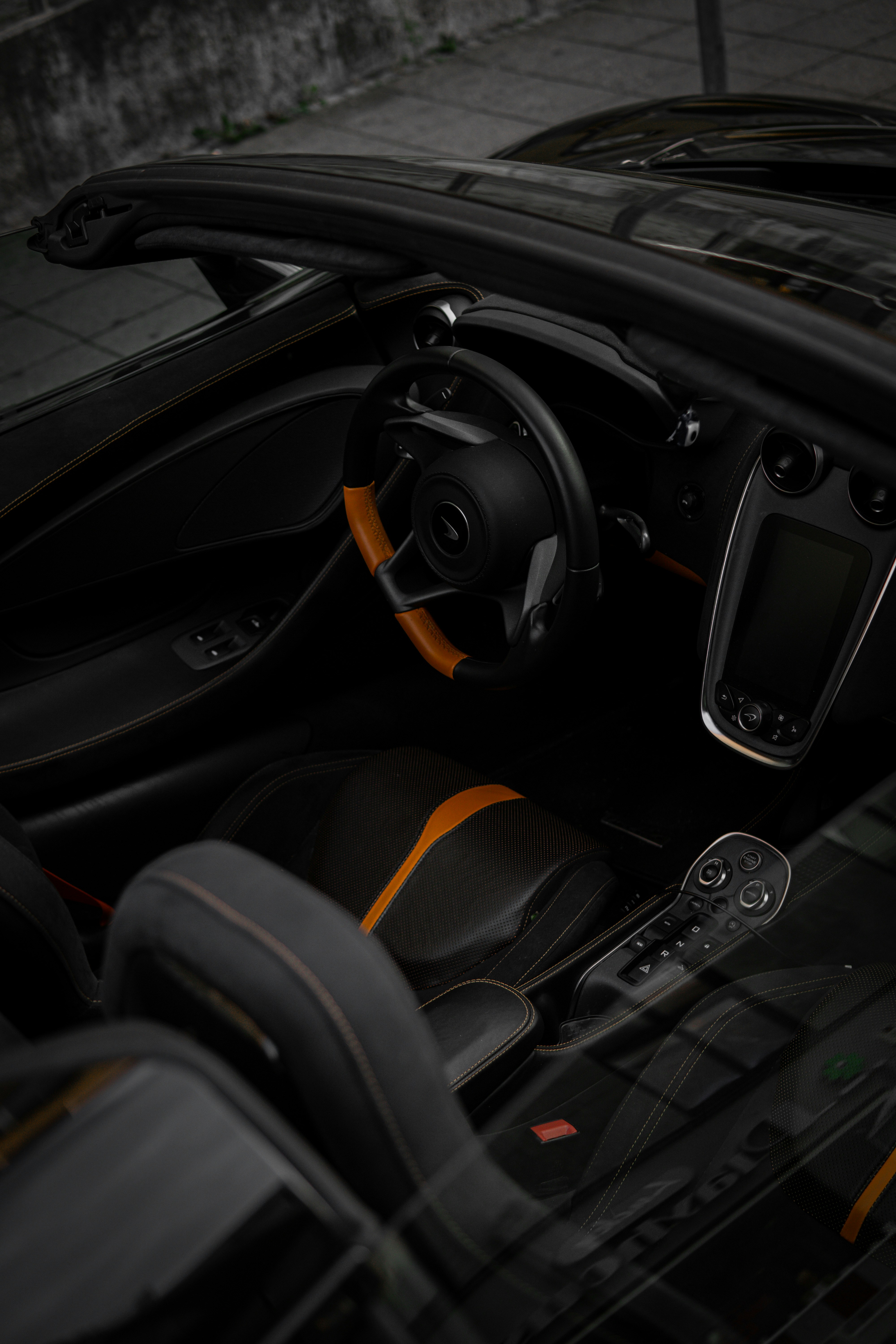 Convertible car interior featuring a leather steering wheel and orange accents.