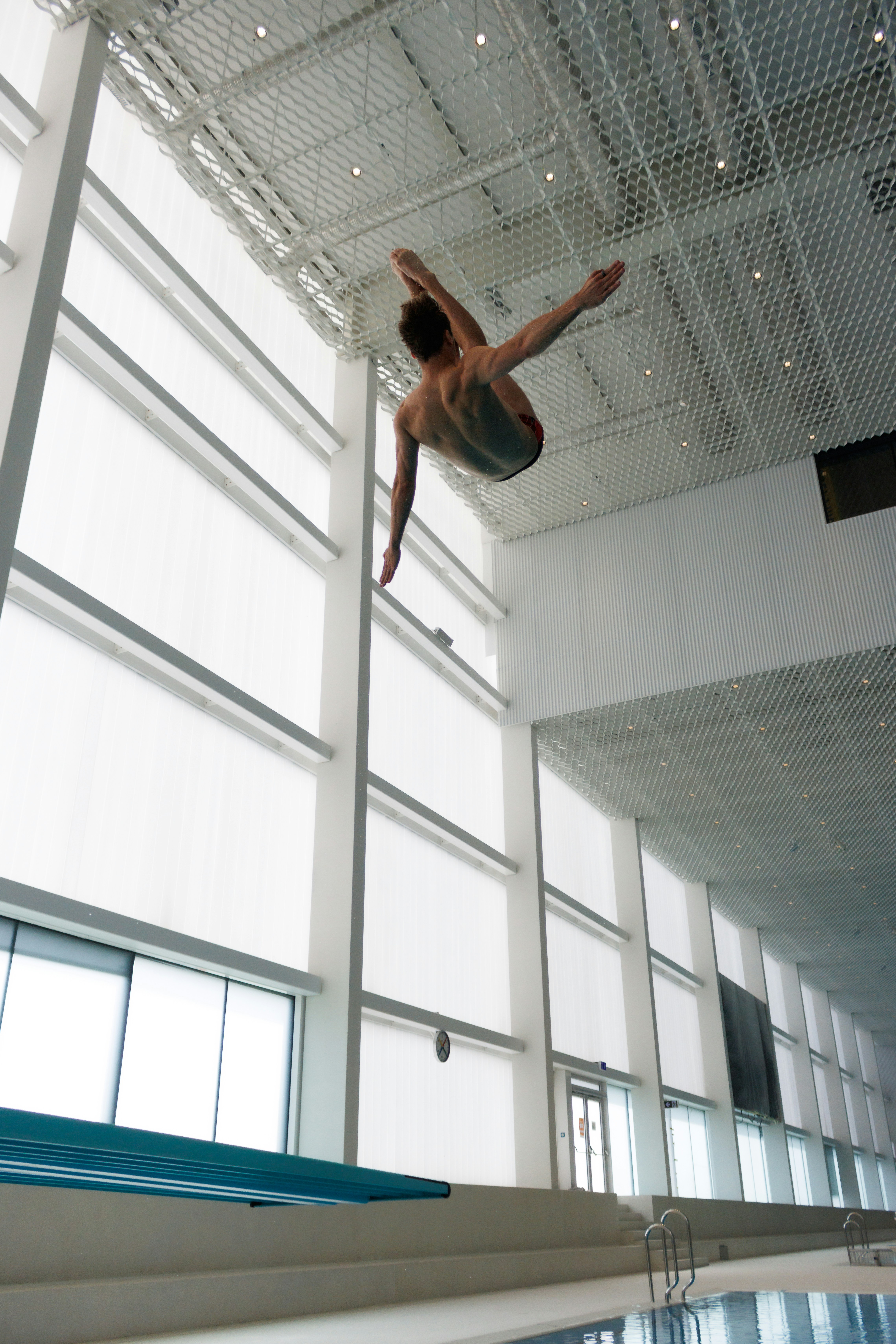 Midair Diver Over a Bright Indoor Pool Hall