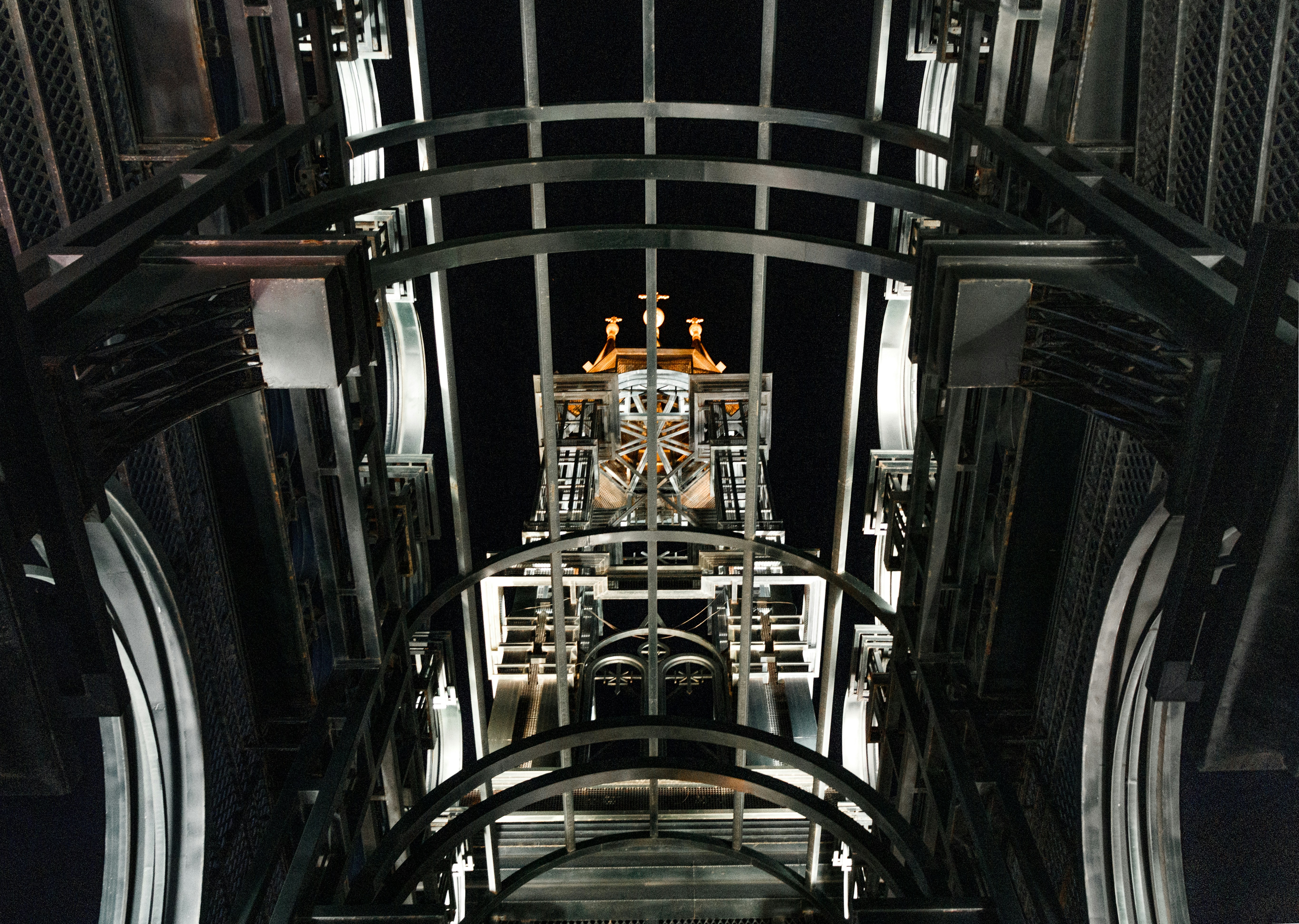 Intricate steel framework converges towards a clock tower, emphasizing the blend of modern engineering and historical elegance.