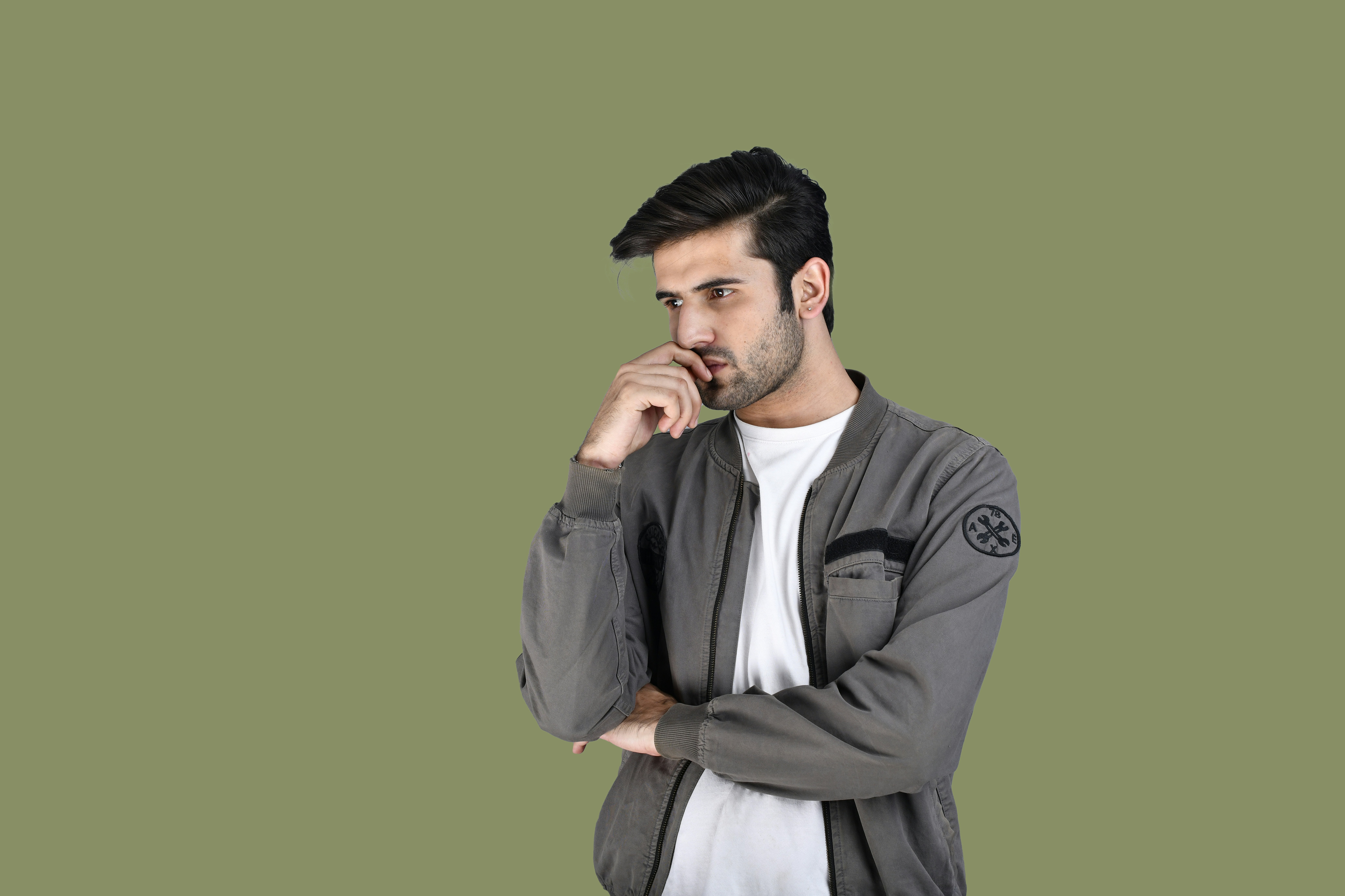 Contemplative gaze: a thoughtful portrait against muted green backdrop