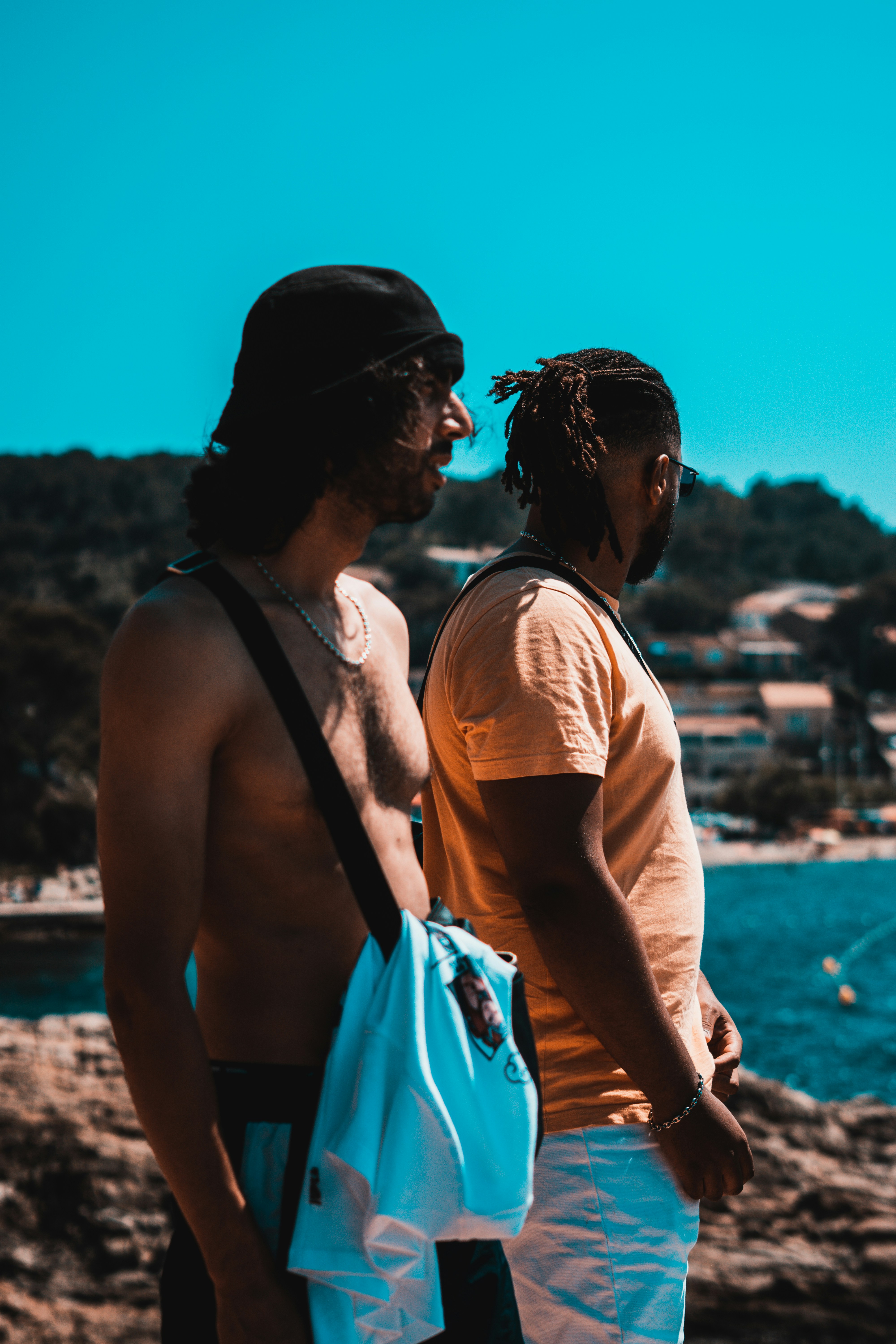 Two Beachgoers in Conversation, Backlit Against a Turquoise Sky