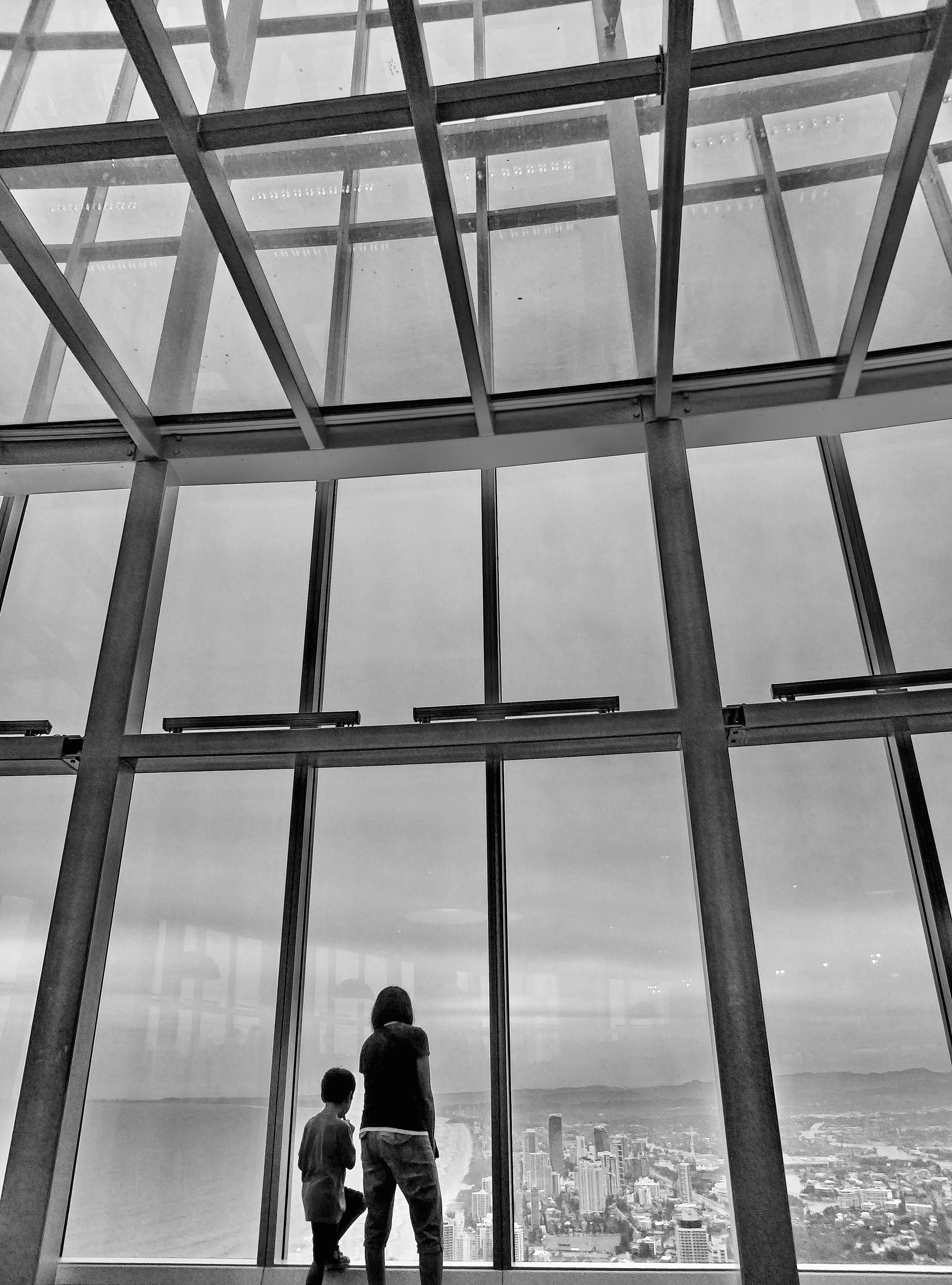 a person and a child looking out a window at a city