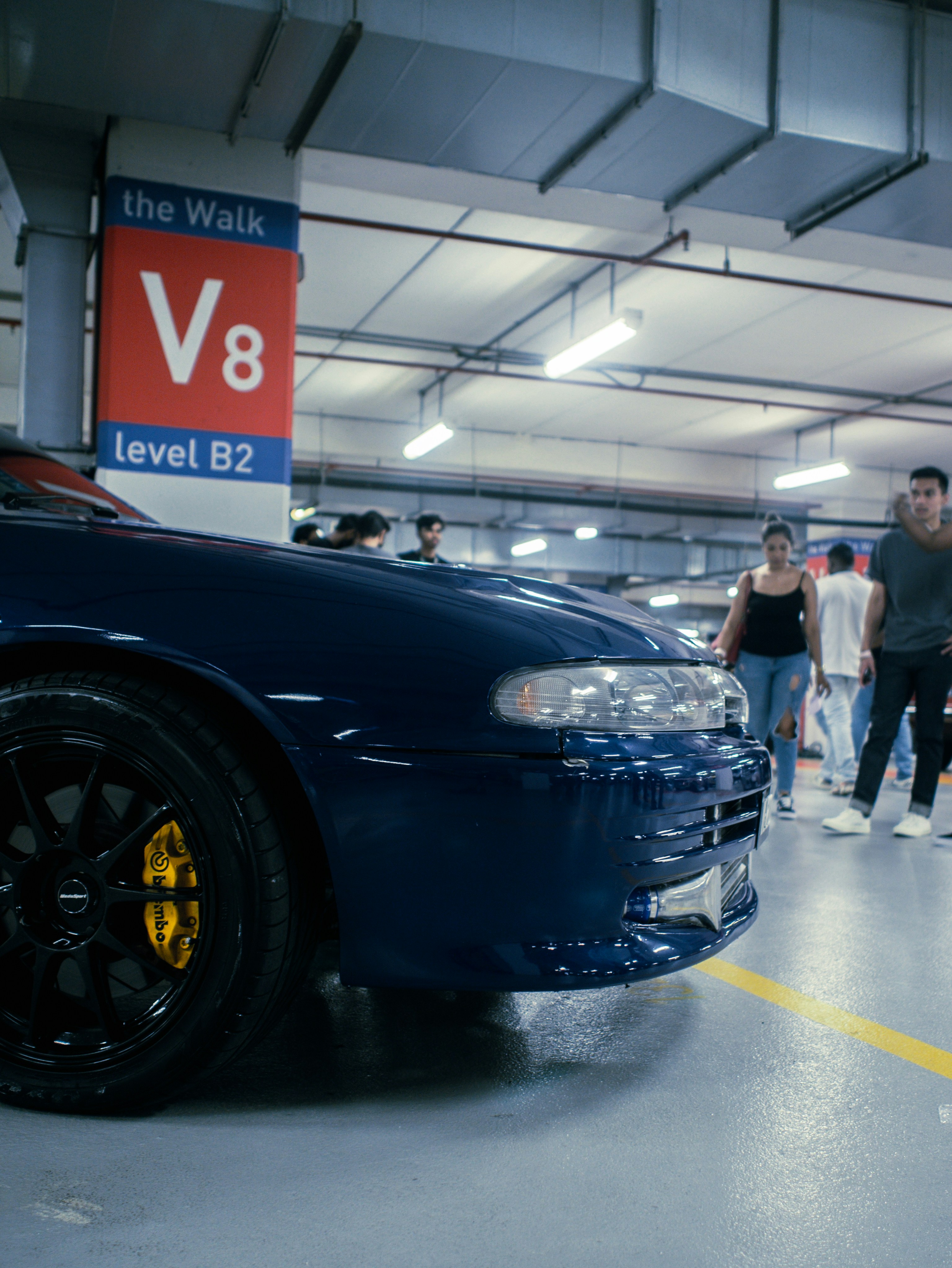 V8 Glint in a Neon Parking Garage: Front-Quarter of a Blue Coupe