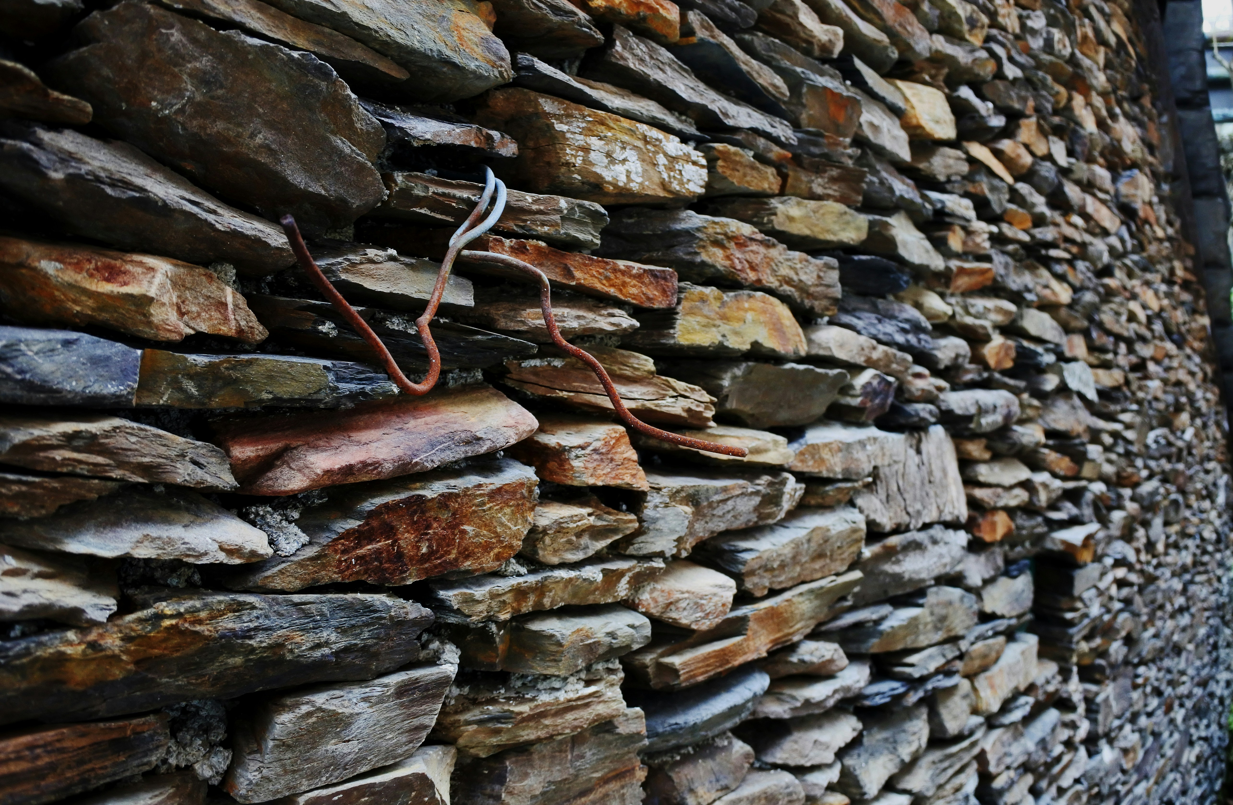 Close-up of a stone wall showcasing the intricate arrangement of natural stones, with metal wires subtly integrated into the design.