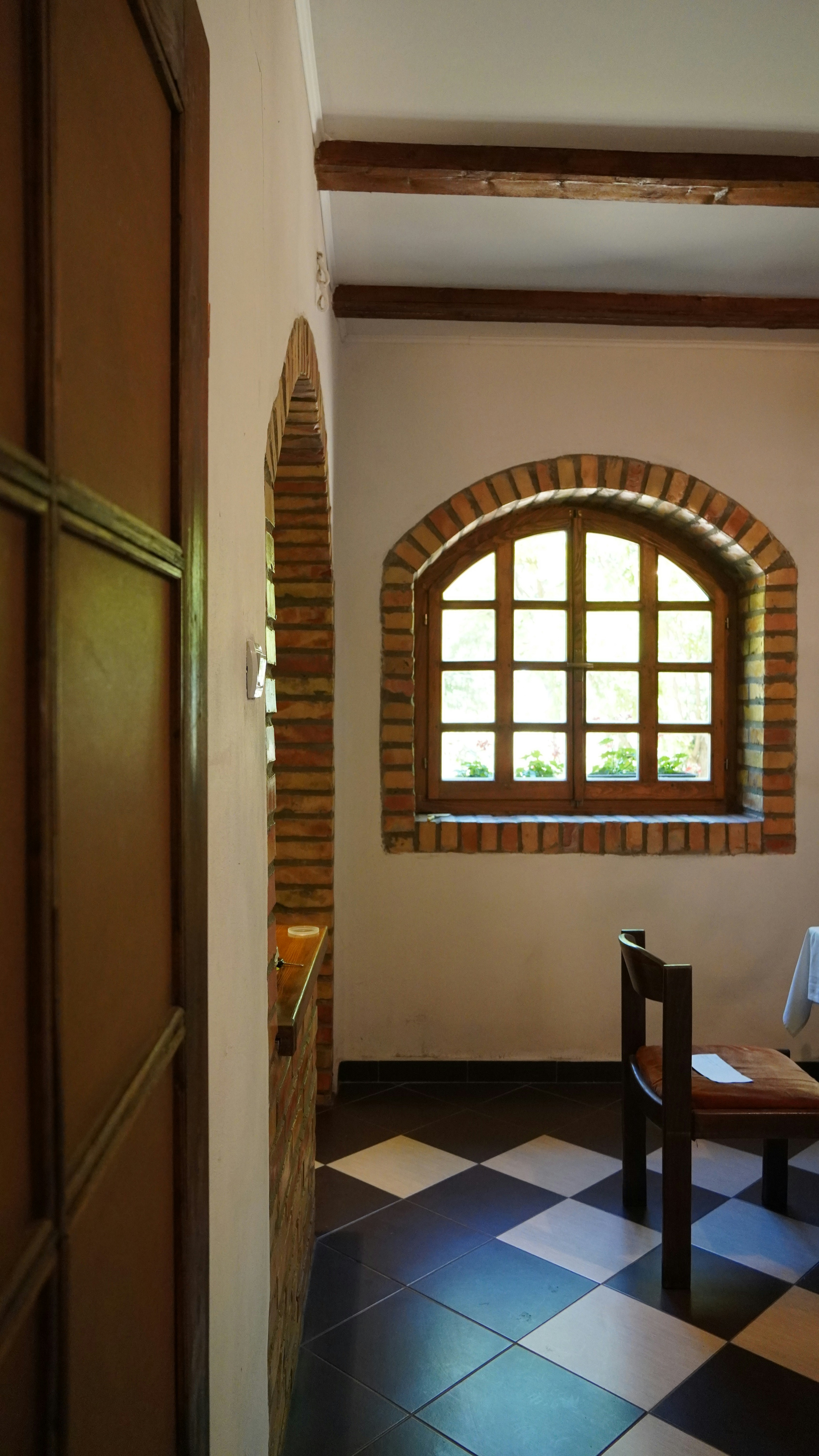 Arched Brick Window Bathes a Quiet Corner in Checkerboard Light