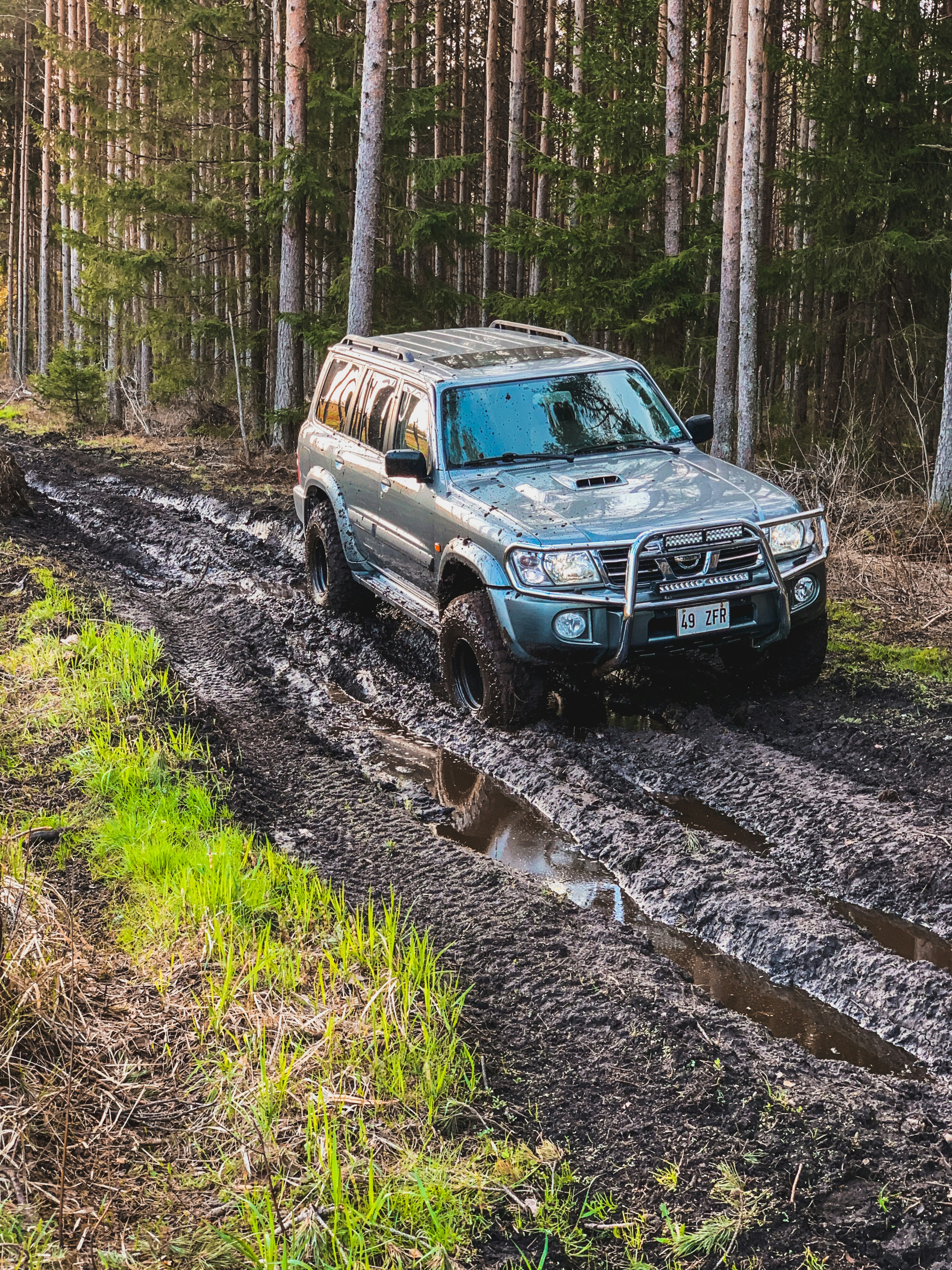 Mud-Clogged Trail King: A Silver SUV Conquers the Wet Woods