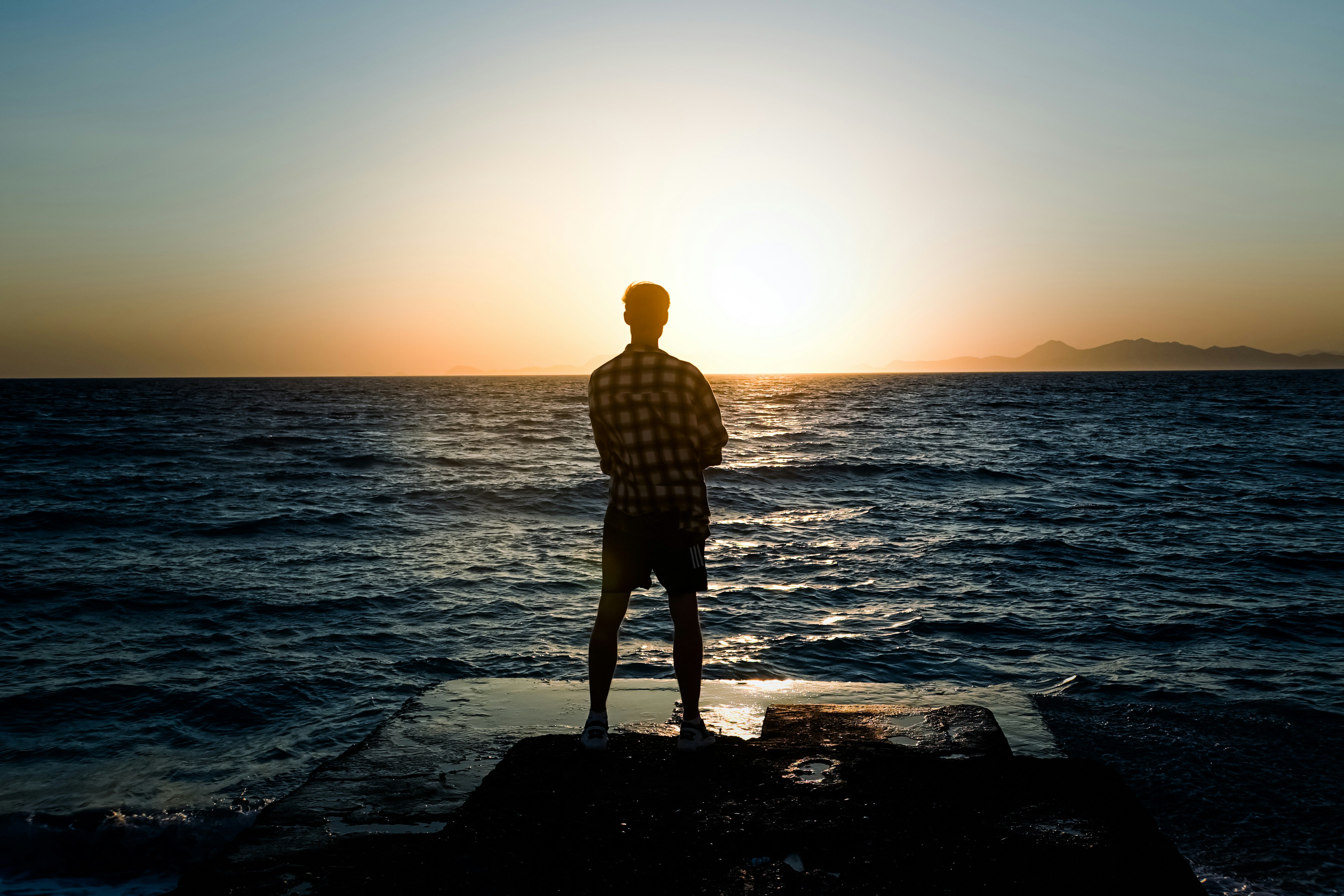 A man standing on a rock looking at the water photo – Free Greece Image ...