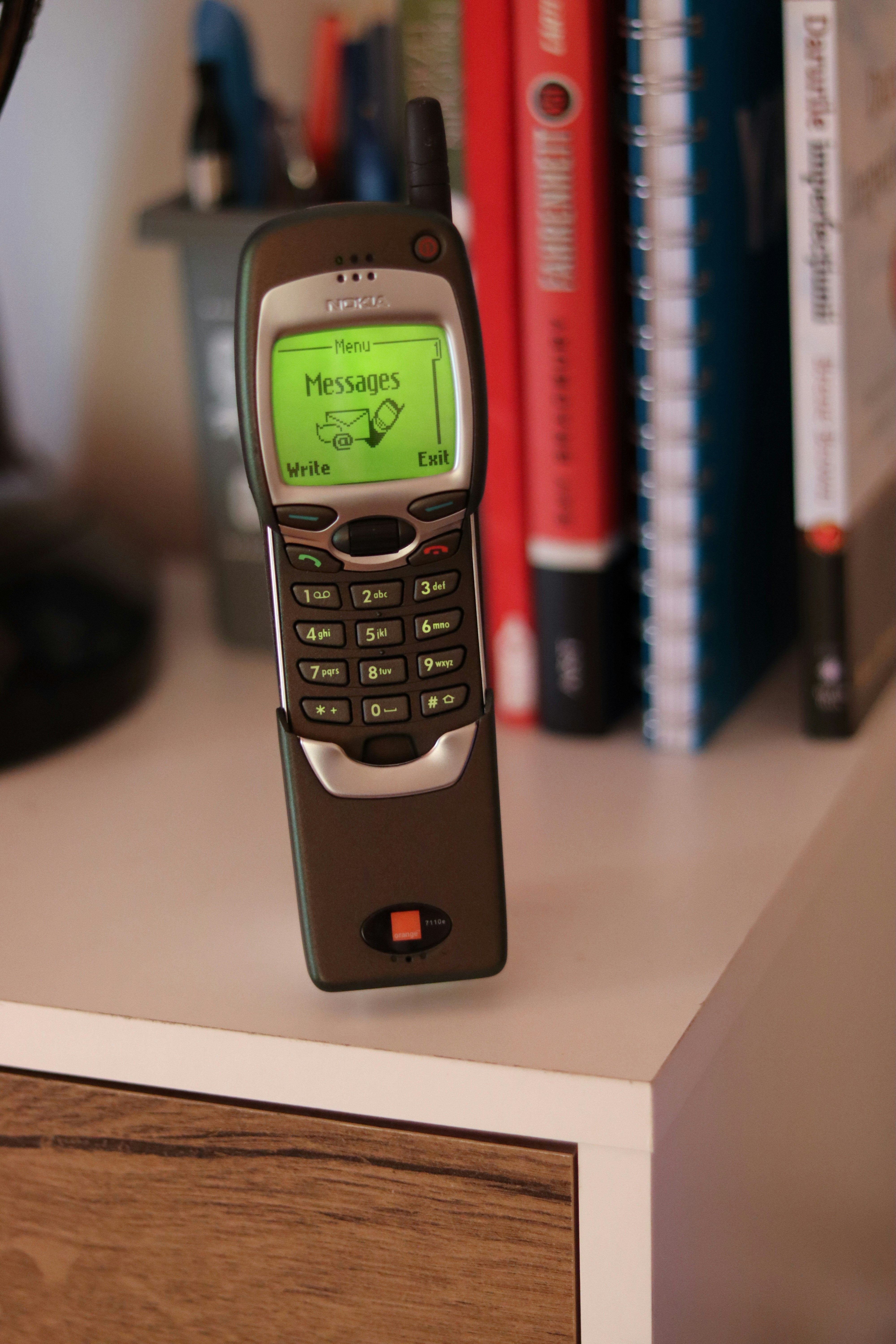 Lime-backlit cordless phone anchors a tidy desk beside a row of manuals