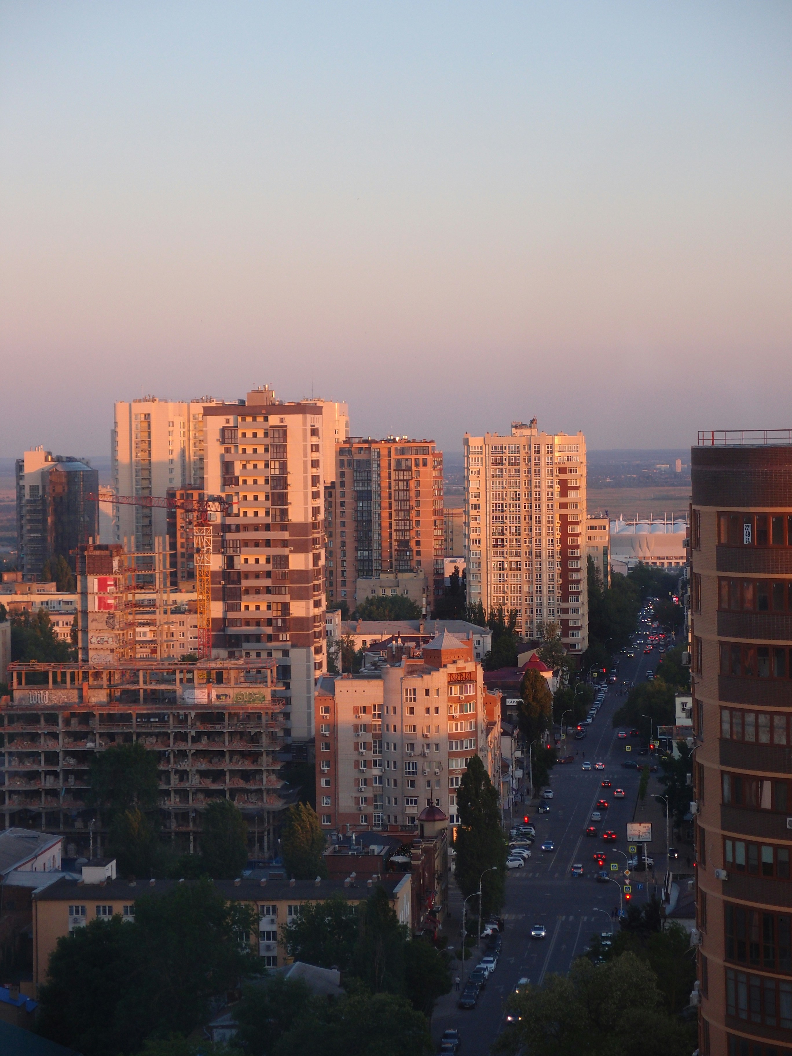 Cityscape at dusk showcasing a blend of modern architecture and urban life with a river in the distance.