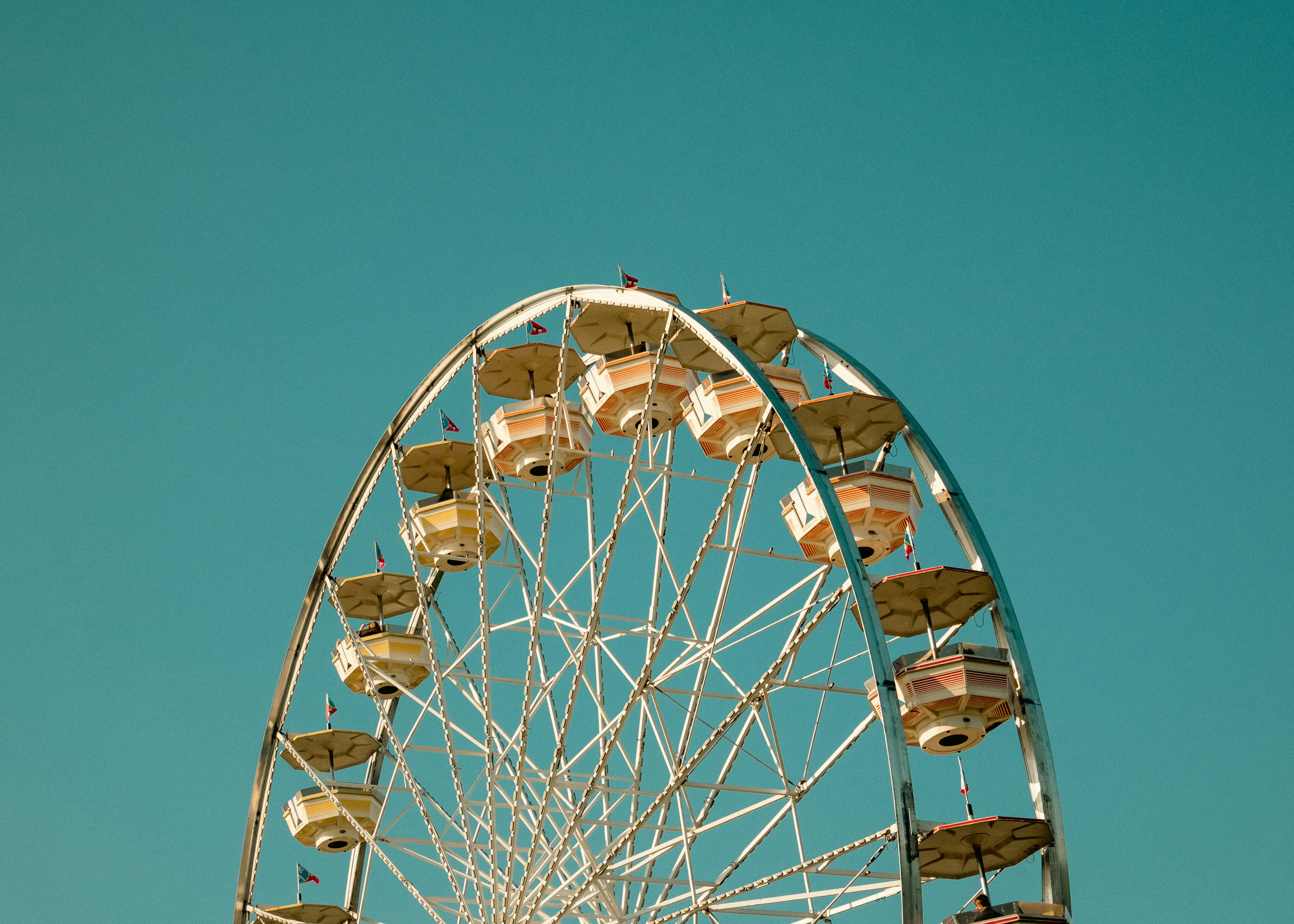 A towering Ferris wheel stands against a clear blue sky, showcasing its colorful gondolas and intricate structure.