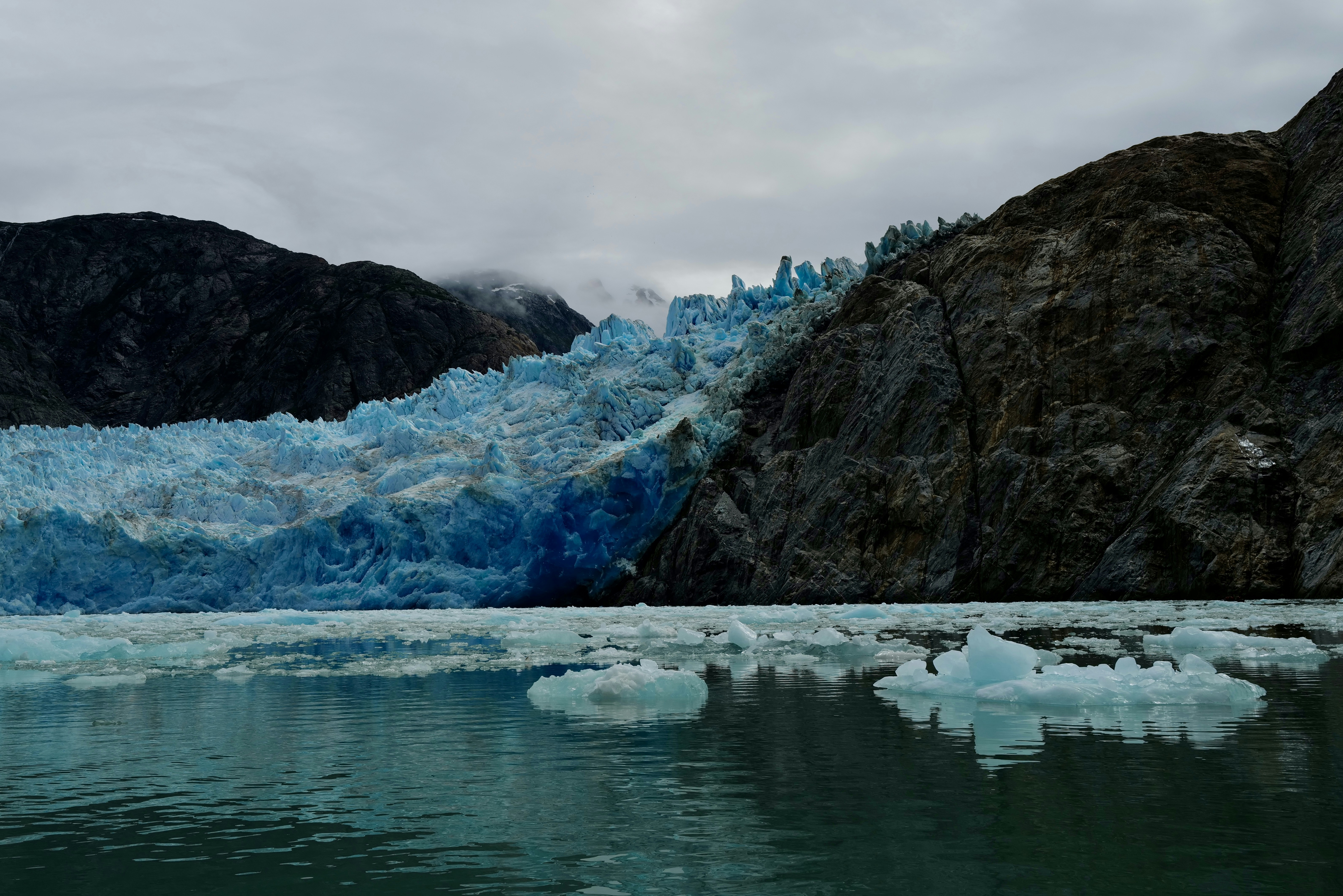 Un cuerpo de agua con hielo y nieve con Tracy Arm en el fondo foto ...