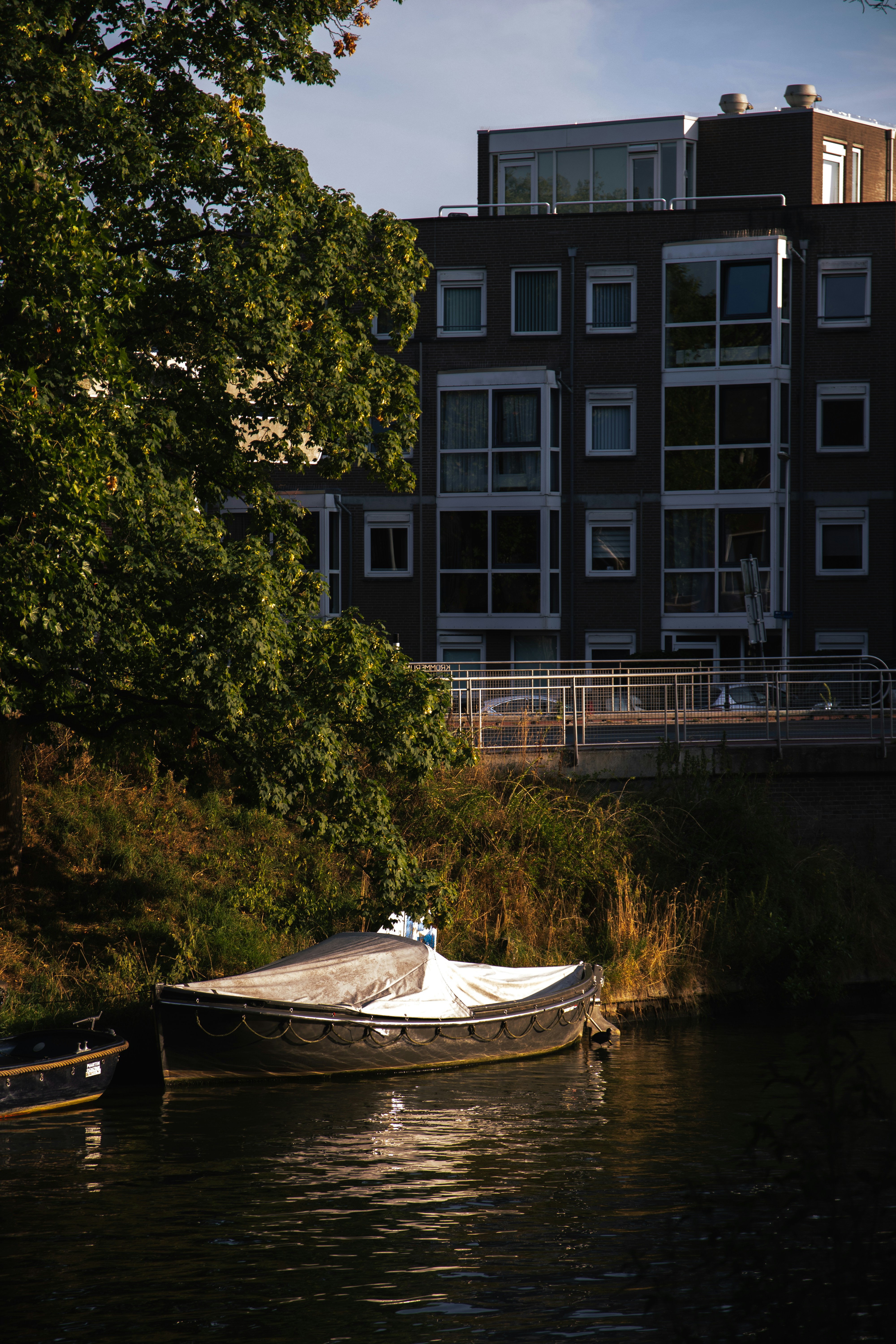 Harbor Quiet: A Boat Nestled by a Modern Riverside Block