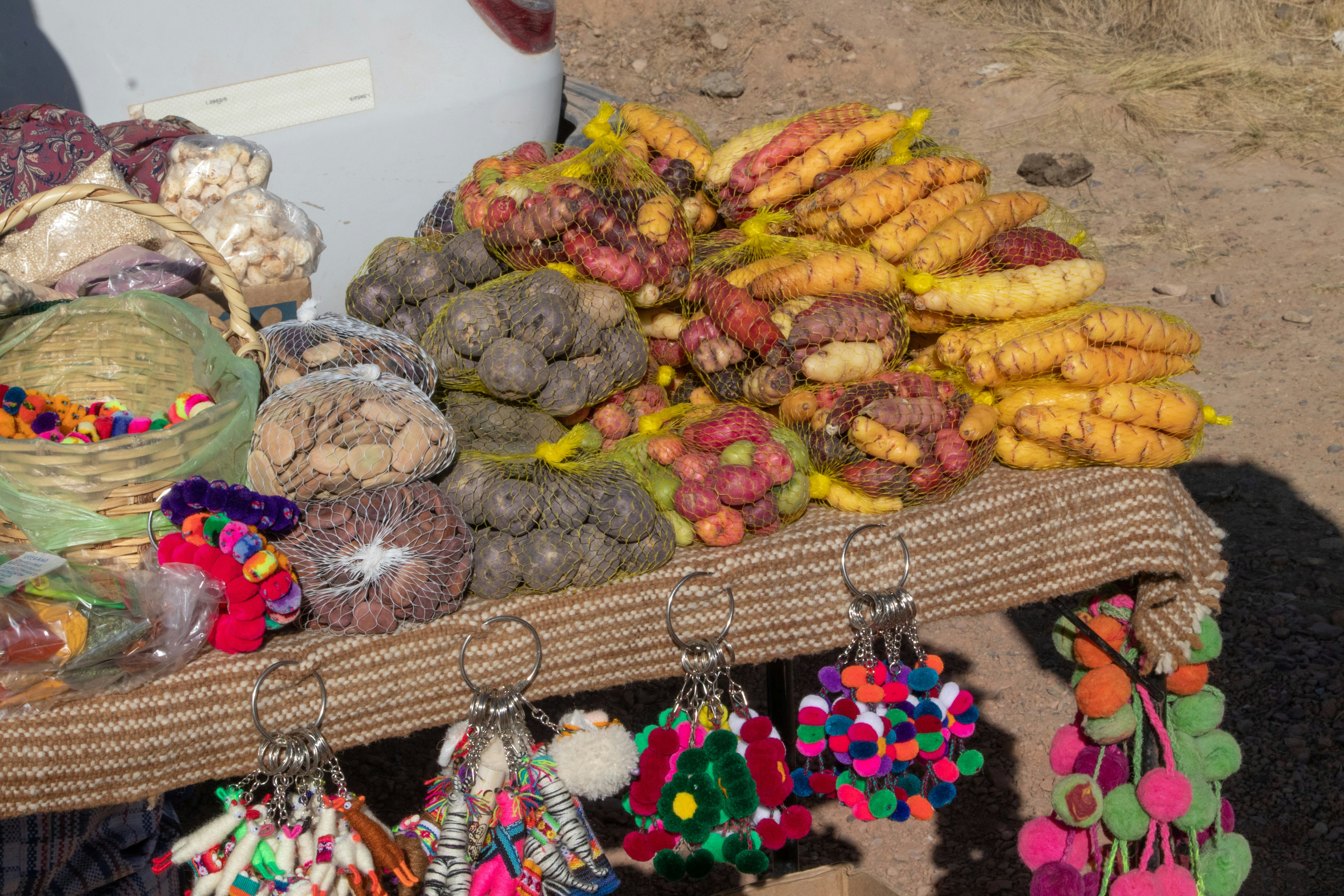 Colorful assortment of root vegetables and handmade crafts displayed at a local market. The array of textures and hues showcases the region's agricultural diversity.